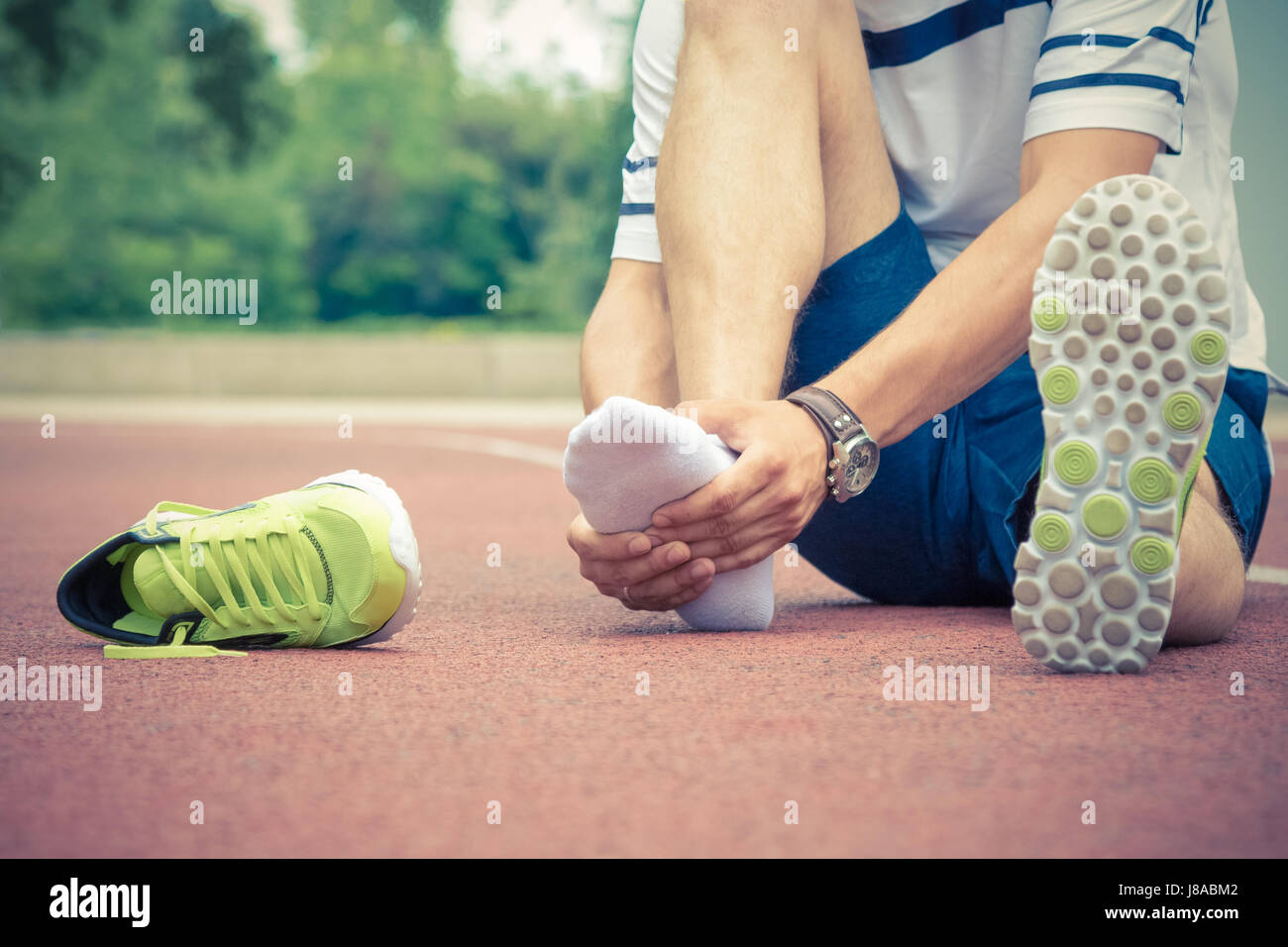 Jogger hands on foot. He is feeling pain as his ankle or foot is broken ...