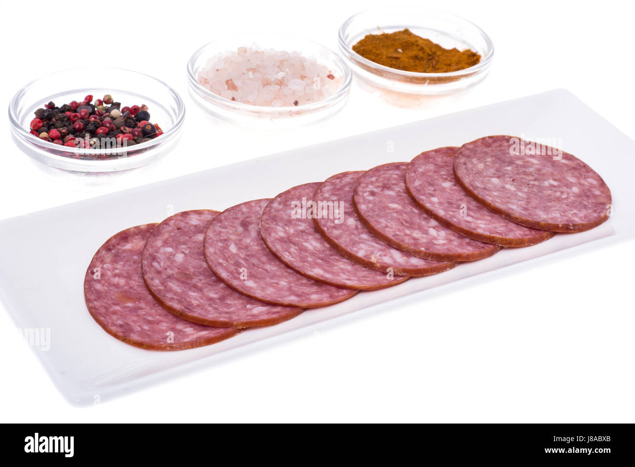 Slices of salami on white plate Stock Photo - Alamy