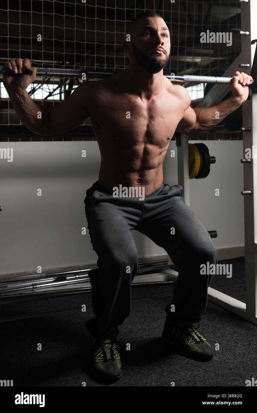Healthy Fitness Man Working Out Legs With Barbell In A Gym - Squat ...