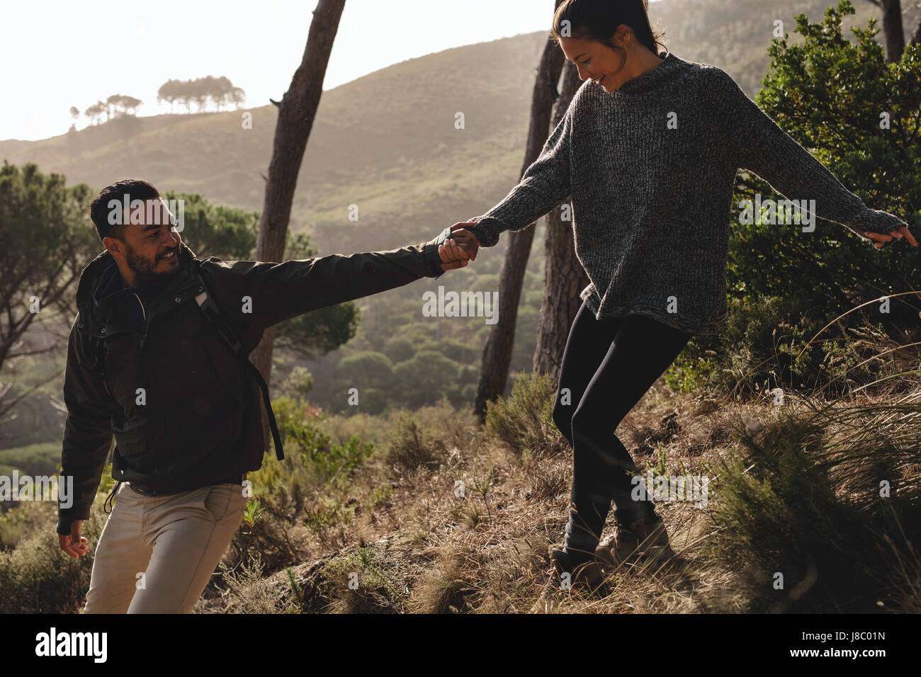 Outdoor shot of young couple enjoying on their hiking trip, walking ...