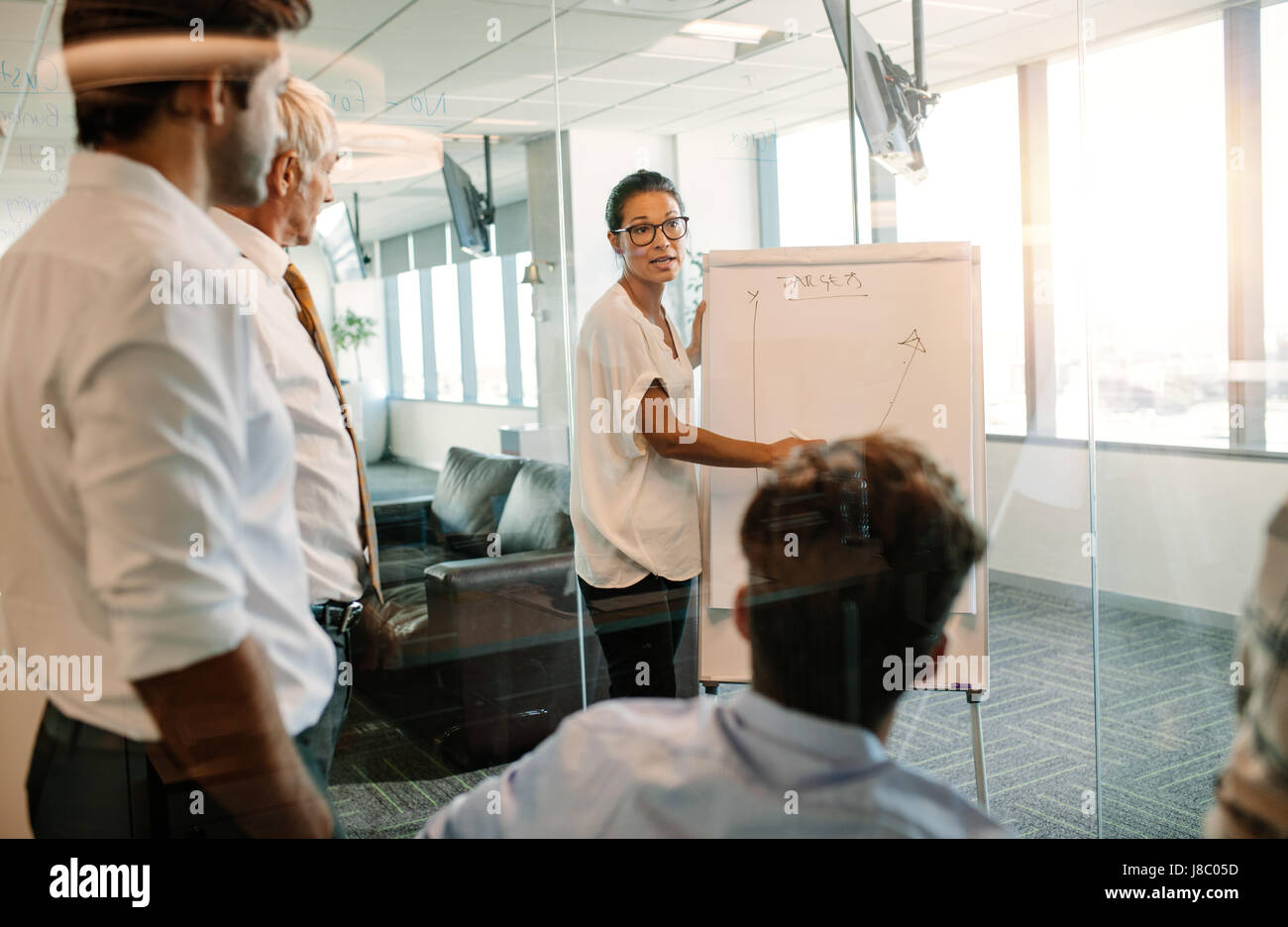 Asian woman standing near flip chart and inputting their ideas ...