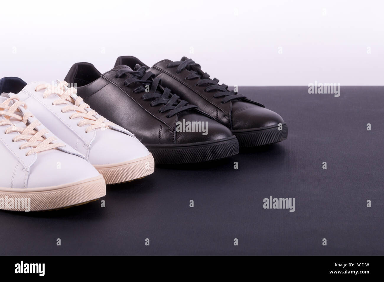 Two pair of sneakers shoes on black background. Black and white shoe ...