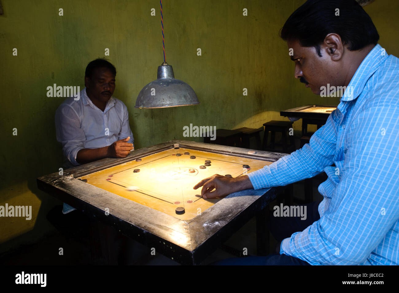 Two men are playing carom in a games room ( India Stock Photo - Alamy