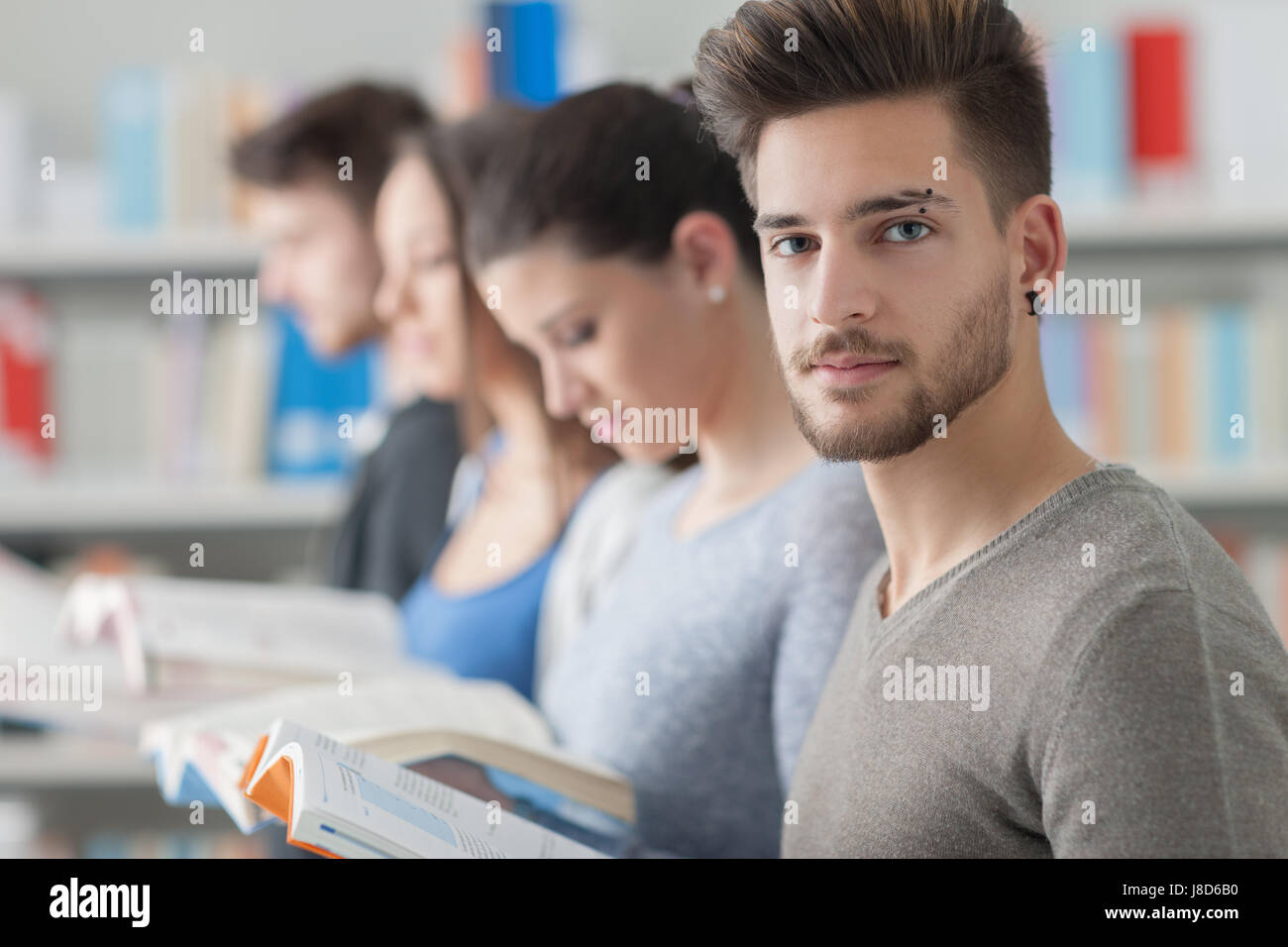 Group of college students in the library standing in line, holding ...