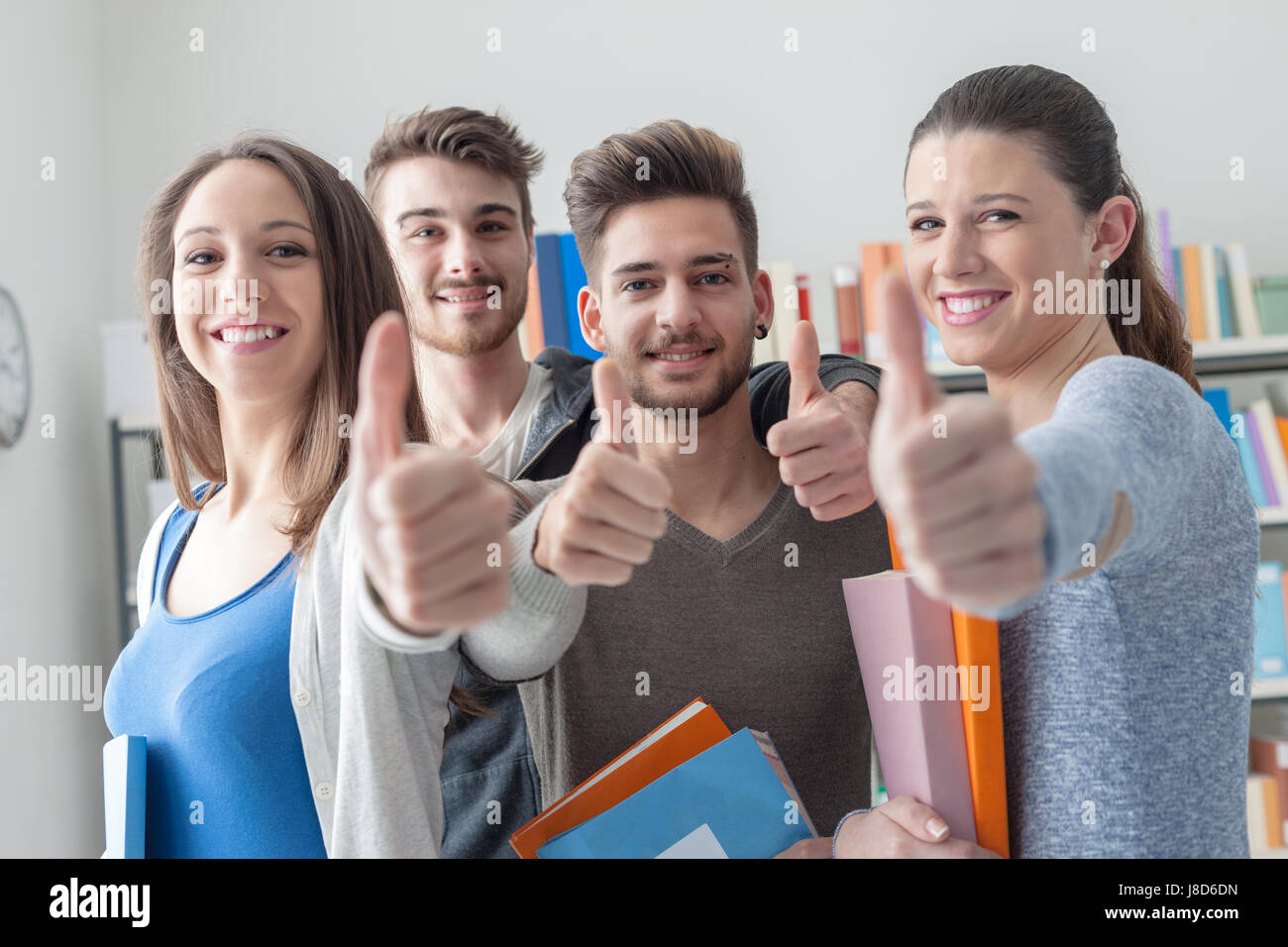 Cheerful group of students smiling at camera with thumbs up, success ...