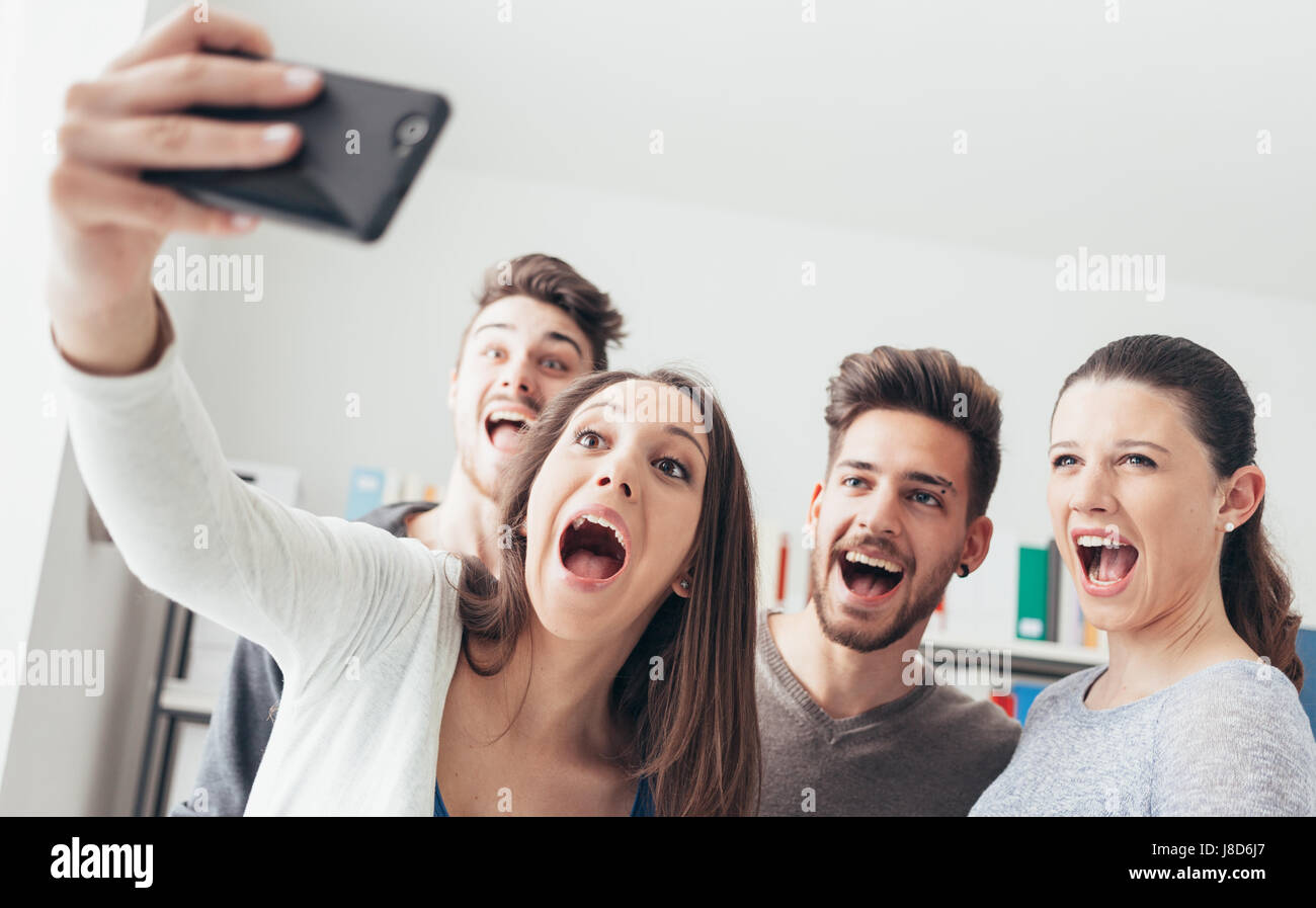 Cheerful teenagers taking self portraits using a touch screen smart ...