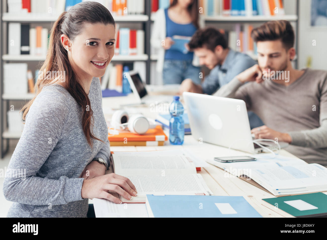 College students sitting at desk and studying together, reading books ...