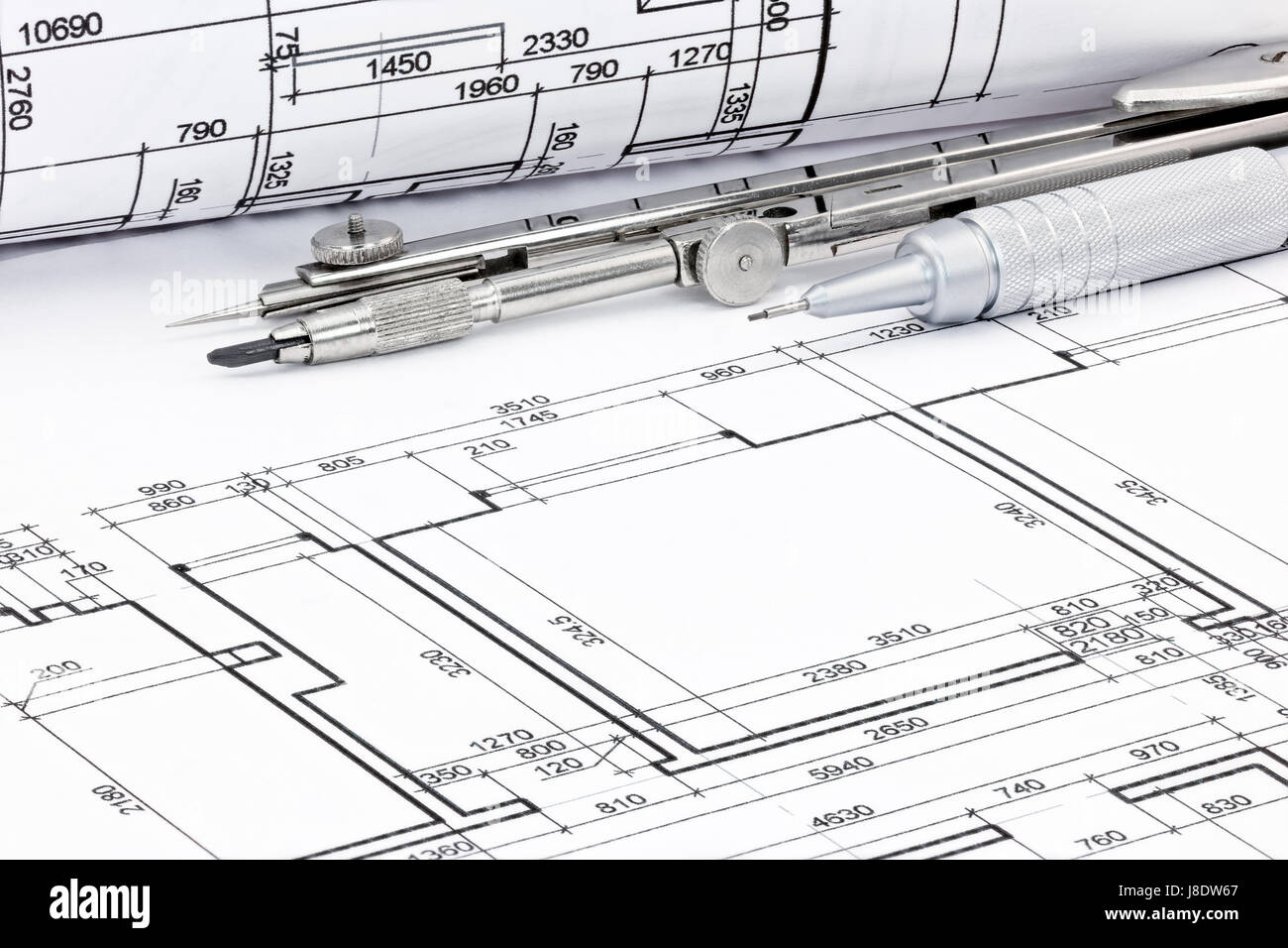 pencil with drawing compass and rolled plans of architectural ...