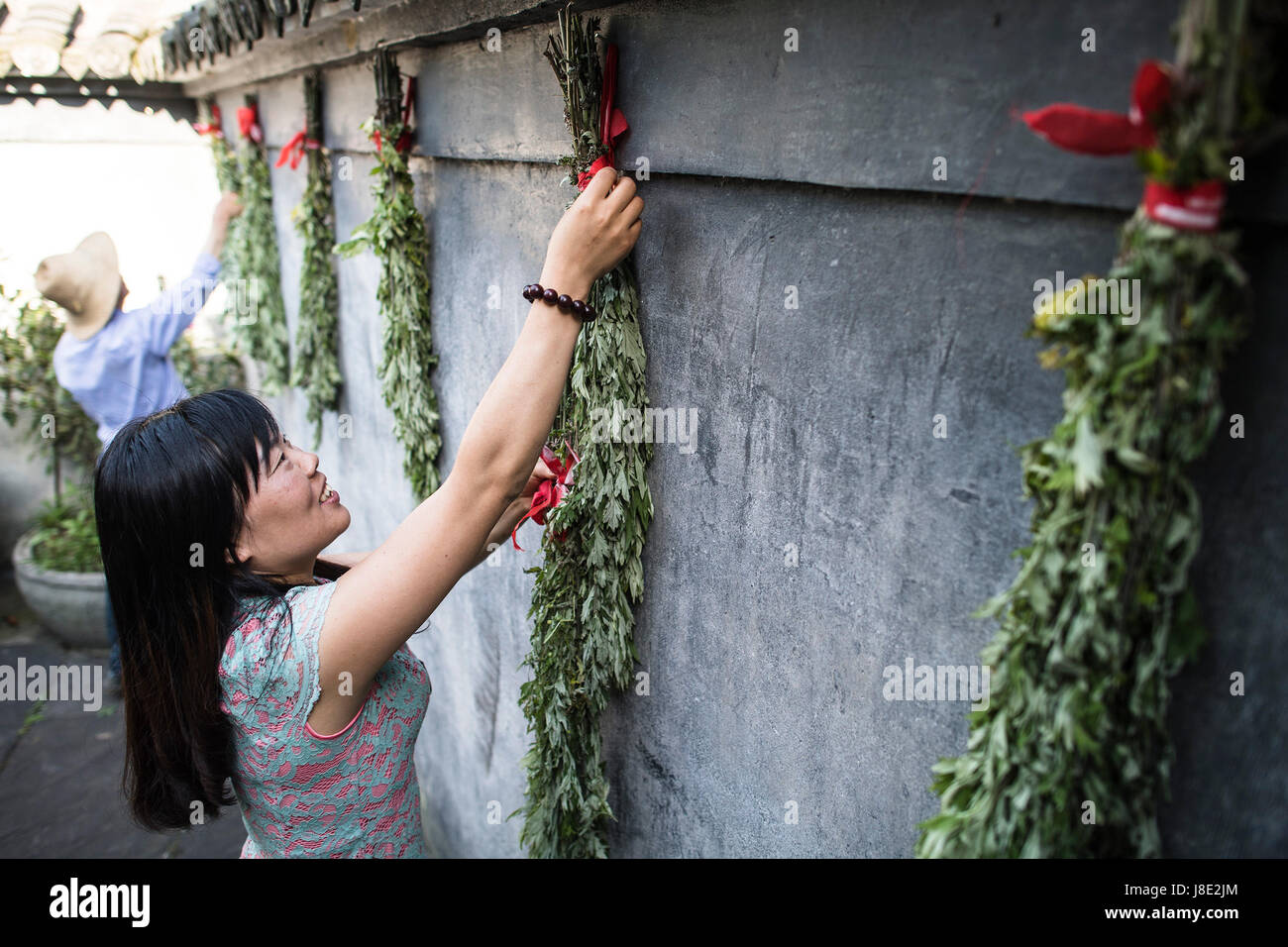Zigui. 27th May, 2017. A woman hangs mugwort leaves on the wall in ...