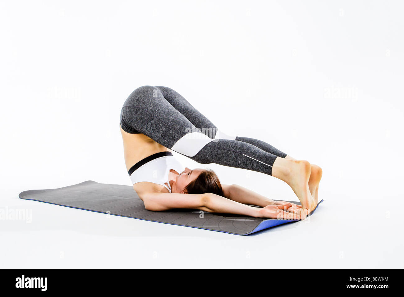 Girl doing stretching on rug at isolated background Stock Photo - Alamy
