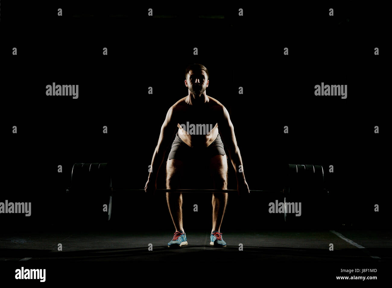 Fitness training. Man doing exercises or training with barbell in dark ...