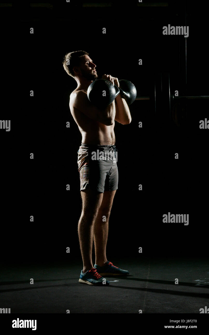 Fitness training. Man doing exercises with weights in dark gym Stock ...
