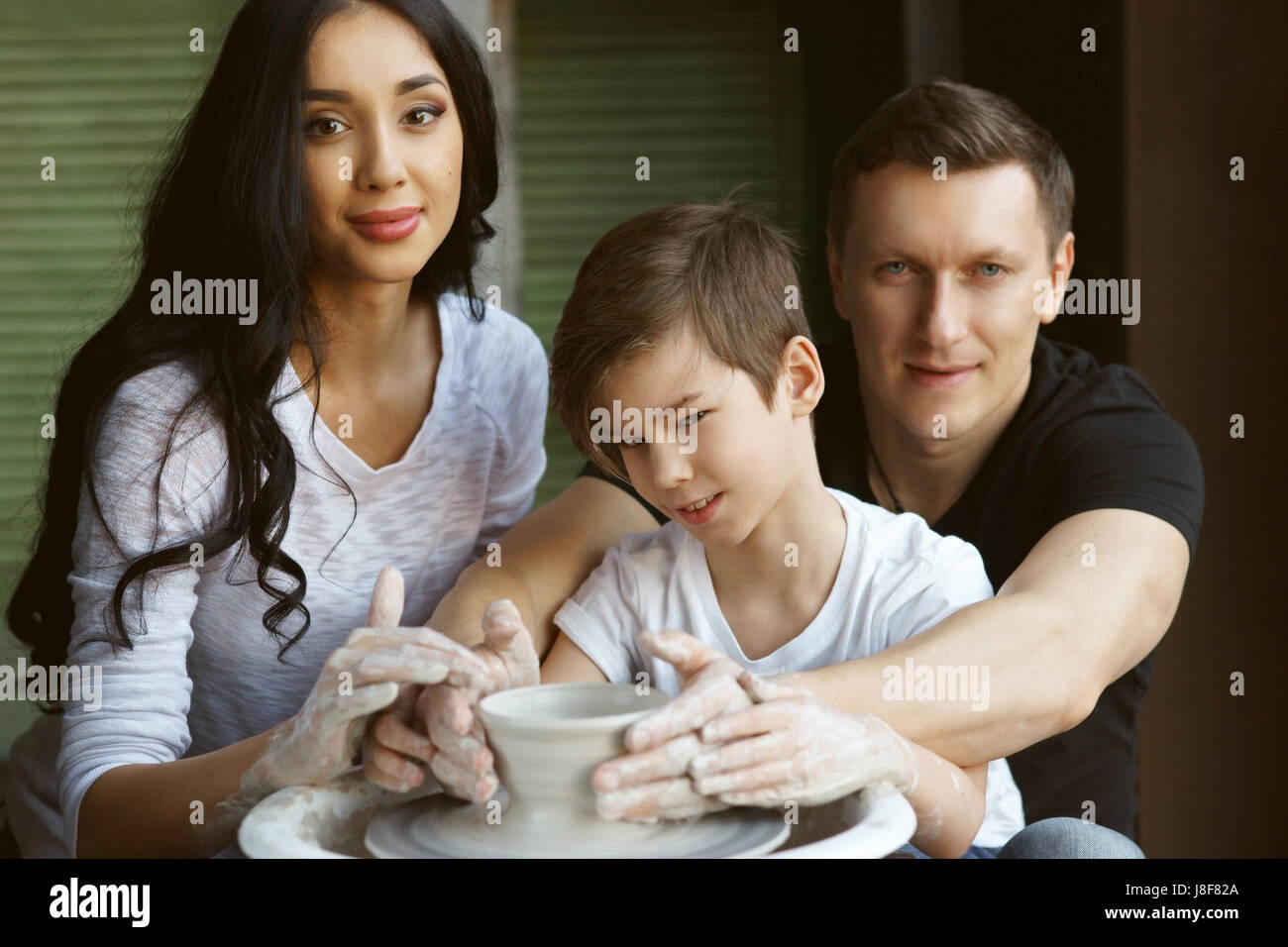 Family working on pottery wheel. Brunette caucasian mother, handsome ...