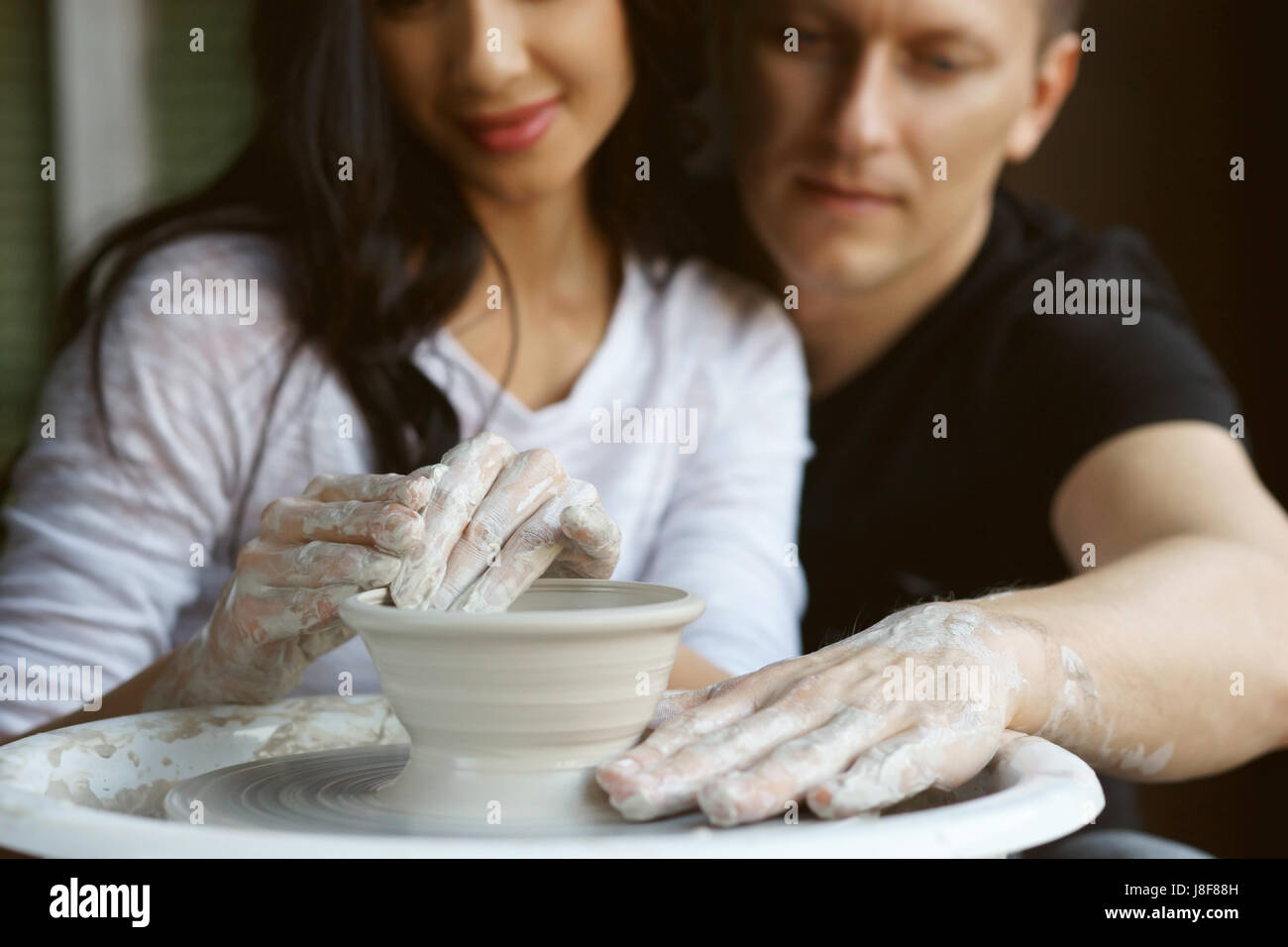 Romantic couple working on potter wheel and making or sculpting clay ...