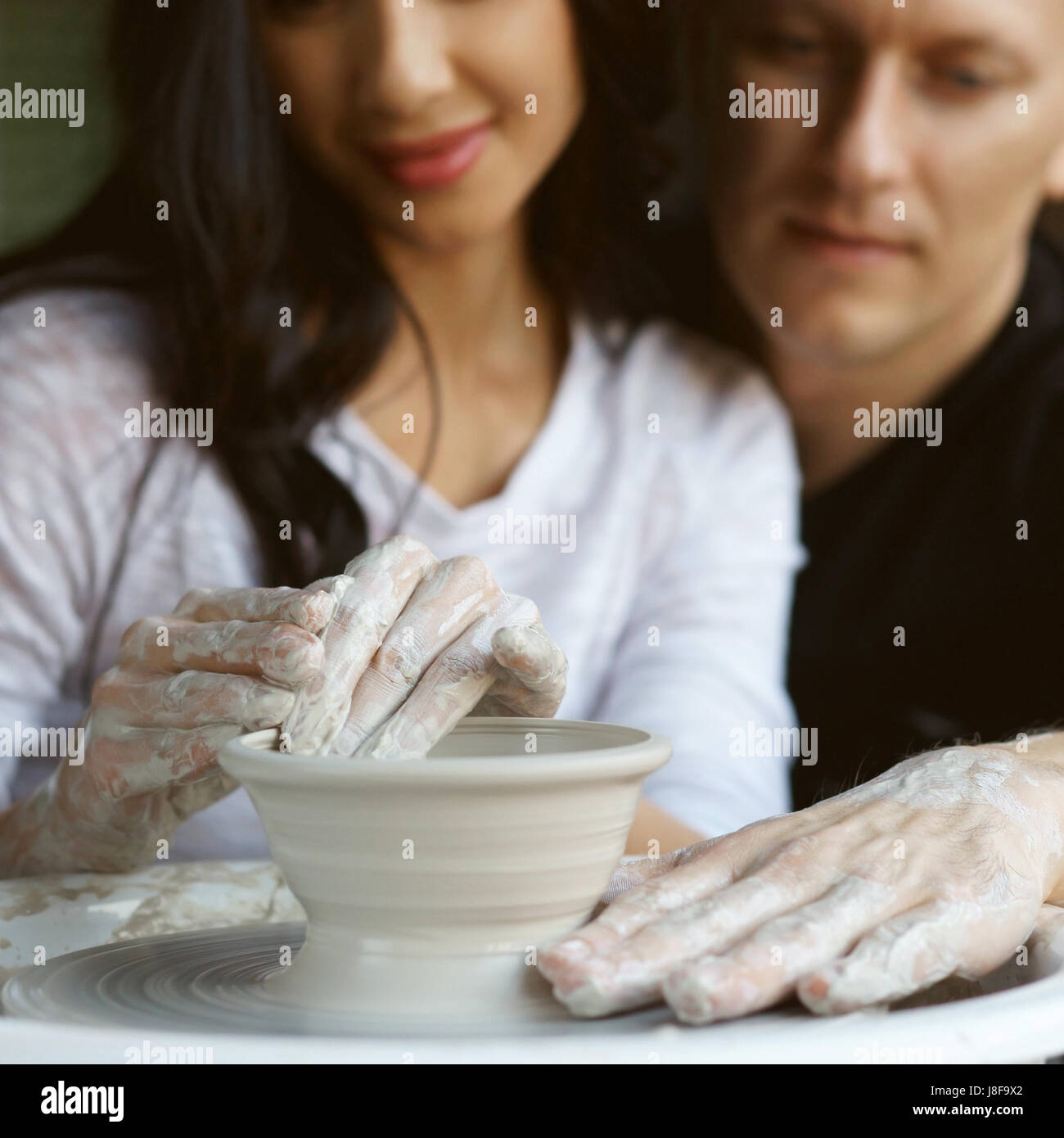Romantic couple working on potter wheel and making or sculpting clay ...