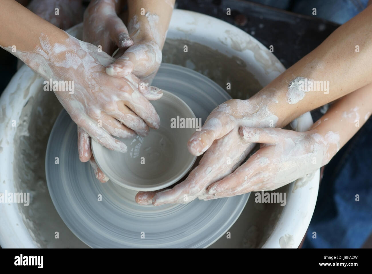Family working on pottery wheel. Top view of mother, father and son ...