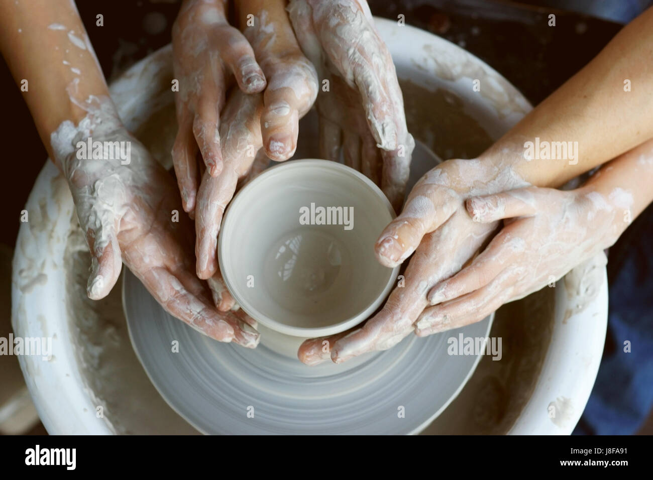 Family working on pottery wheel. Top view of mother, father and son ...