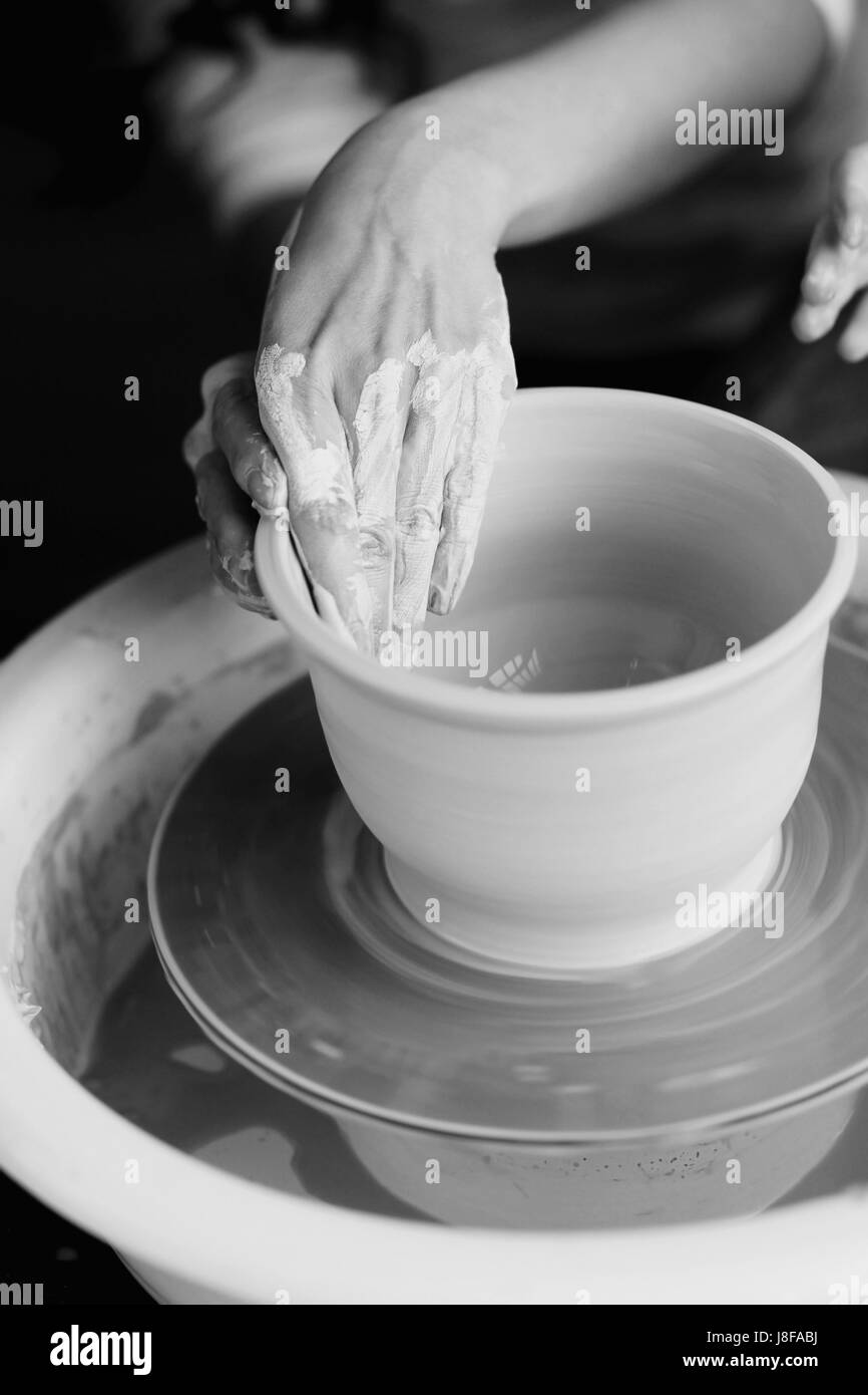 Woman working on potters wheel making dishes with their own hands ...