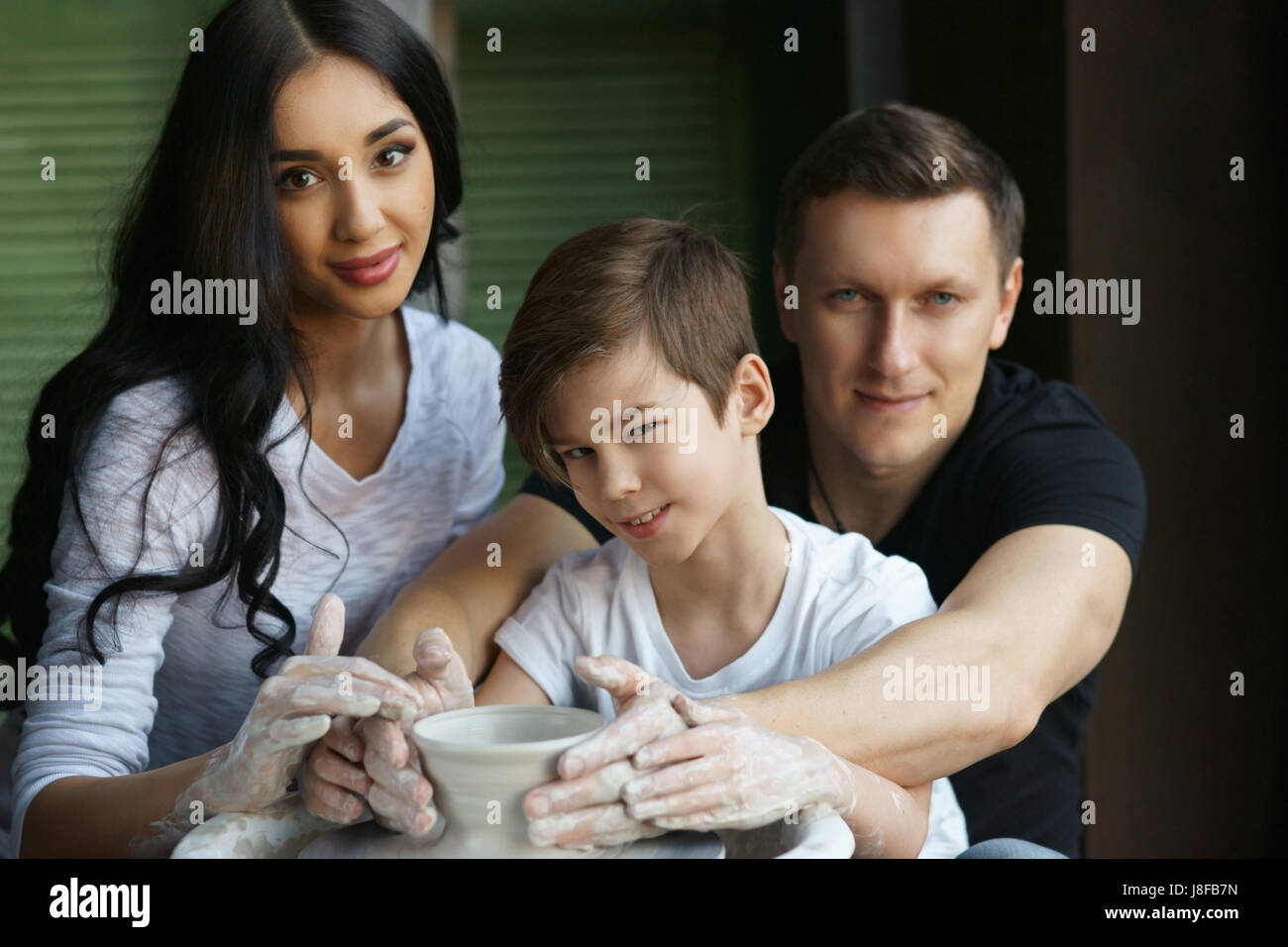 Family working on pottery wheel. Handsome father and beautiful mother ...