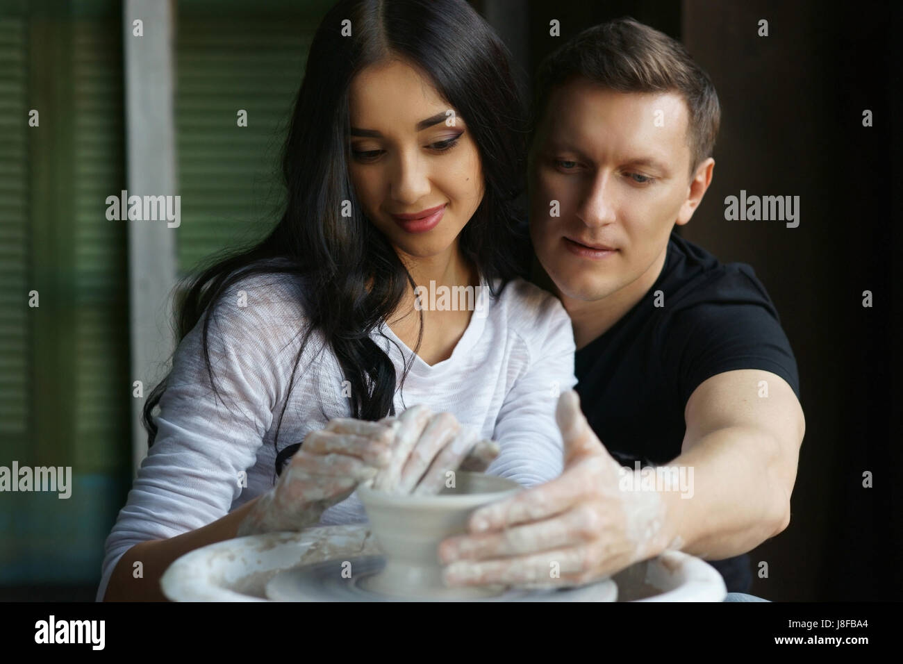 Pottery couple making clay pot on potter's wheel. Handsome man and ...