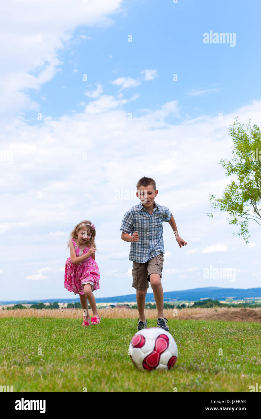 siblings playing soccer in the garden Stock Photo - Alamy