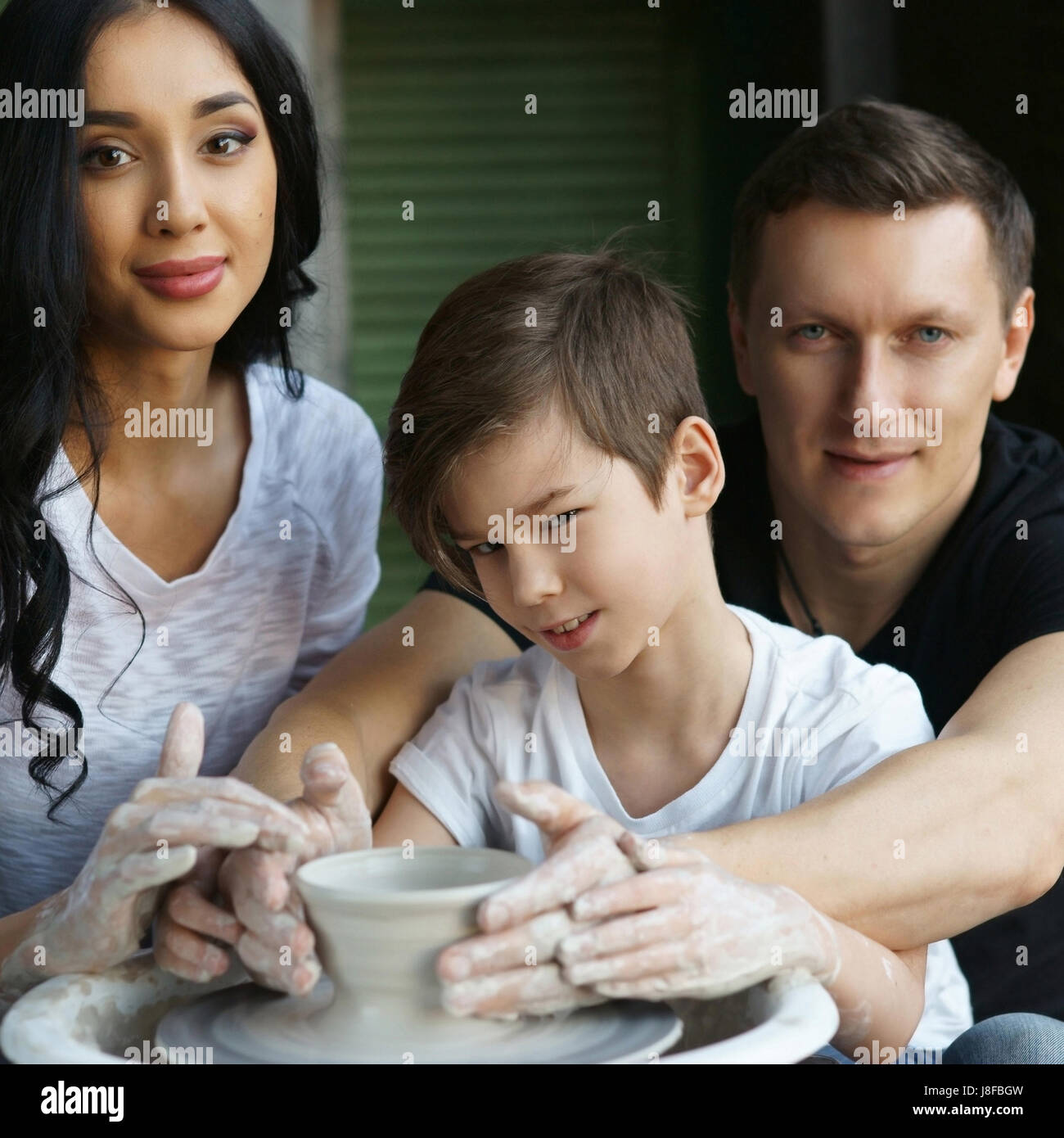 Family working on pottery wheel. Brunette caucasian mother, handsome ...