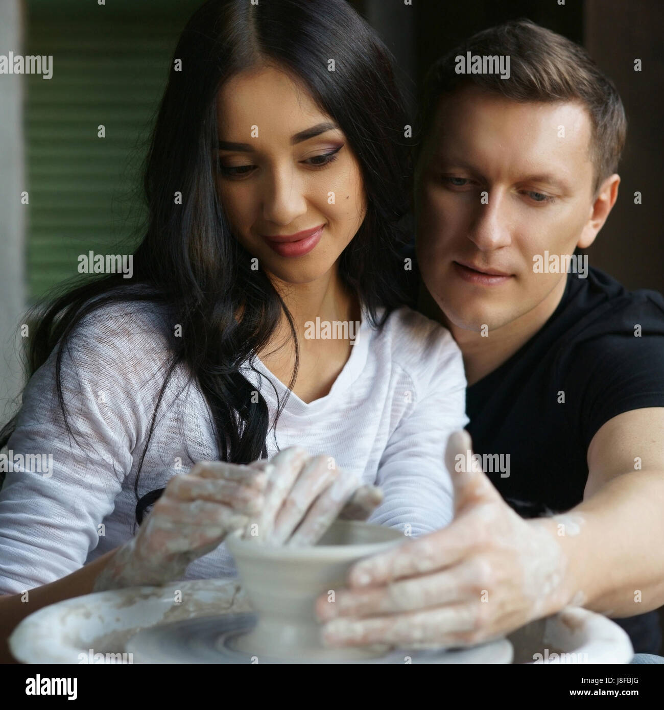 Pottery couple making clay pot on potter's wheel. Handsome man and ...