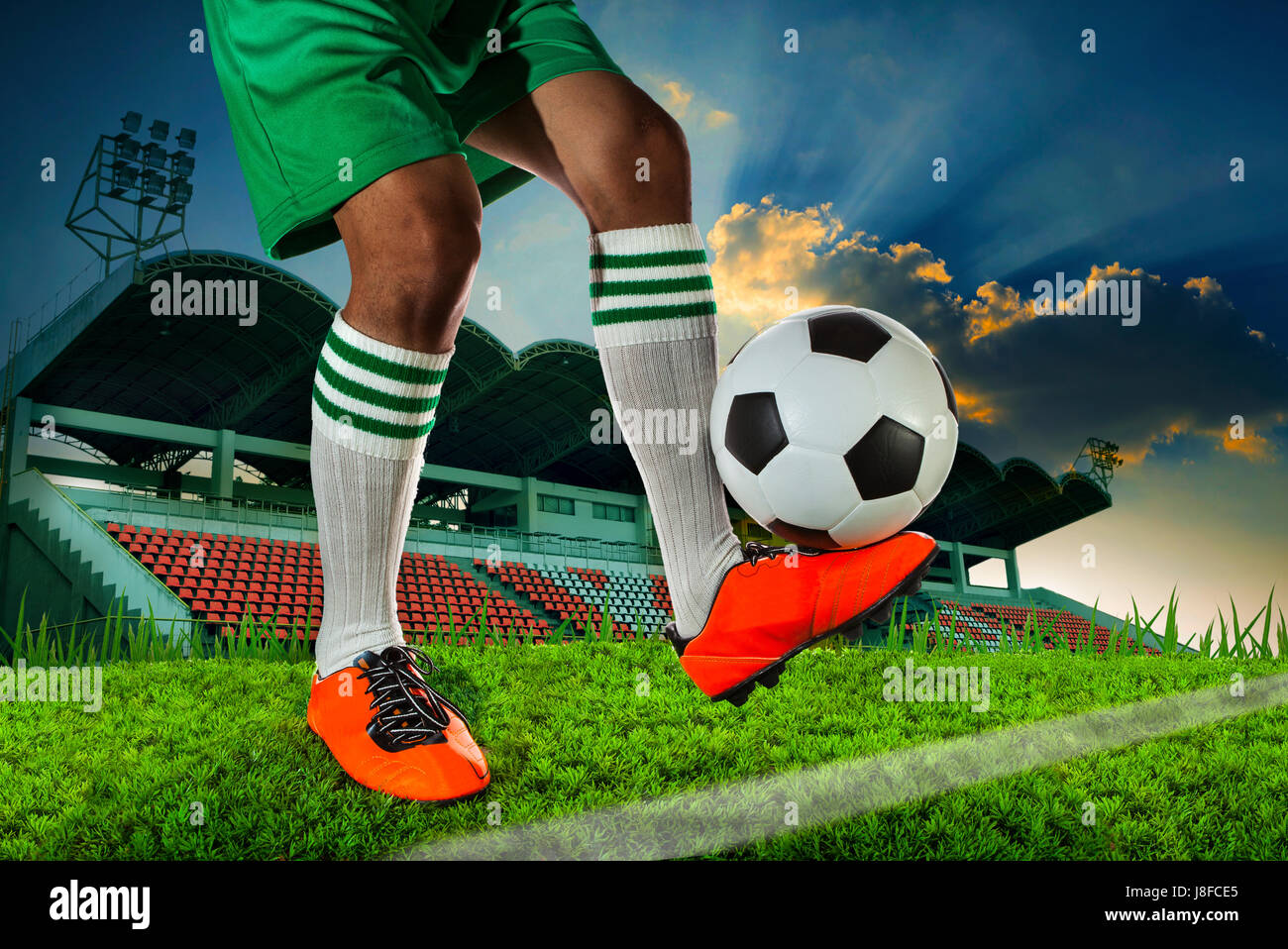 foot ball player holding foot ball on leg ankle on soccer sport field ...