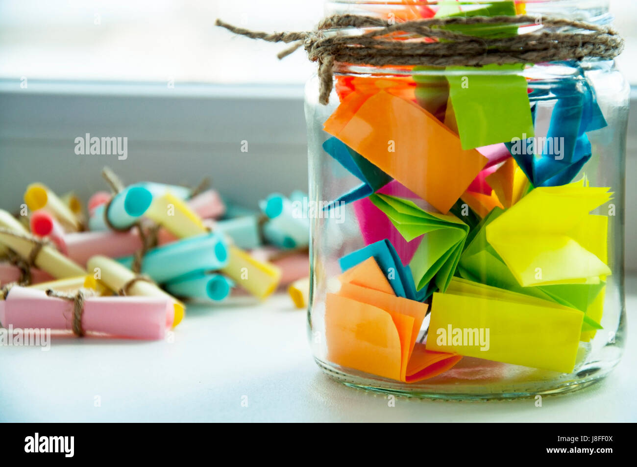 Glass jar with colored notes with blur and toning Stock Photo - Alamy