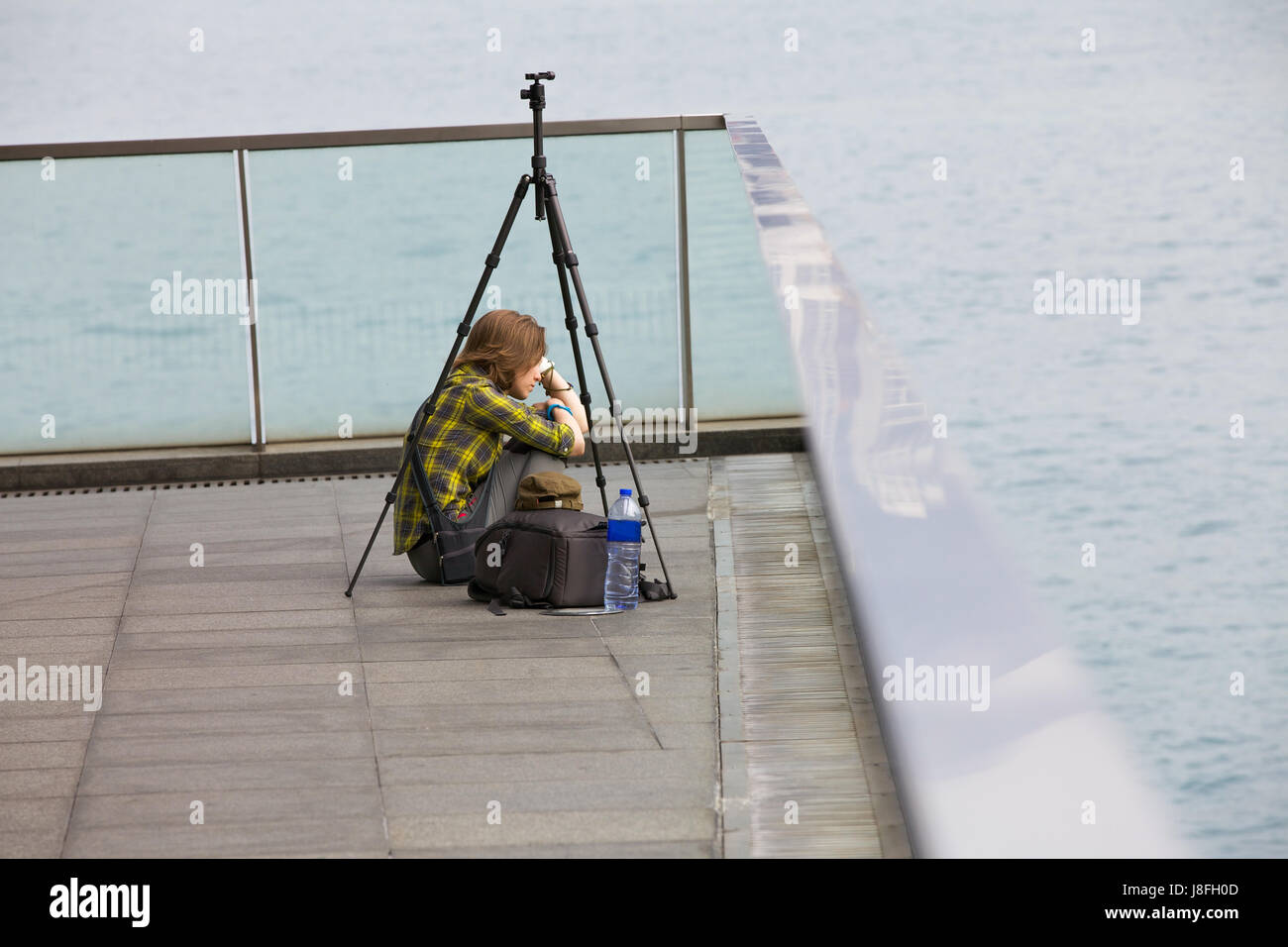 Sad young woman with a backpack and a bottle of water sitting on the ...