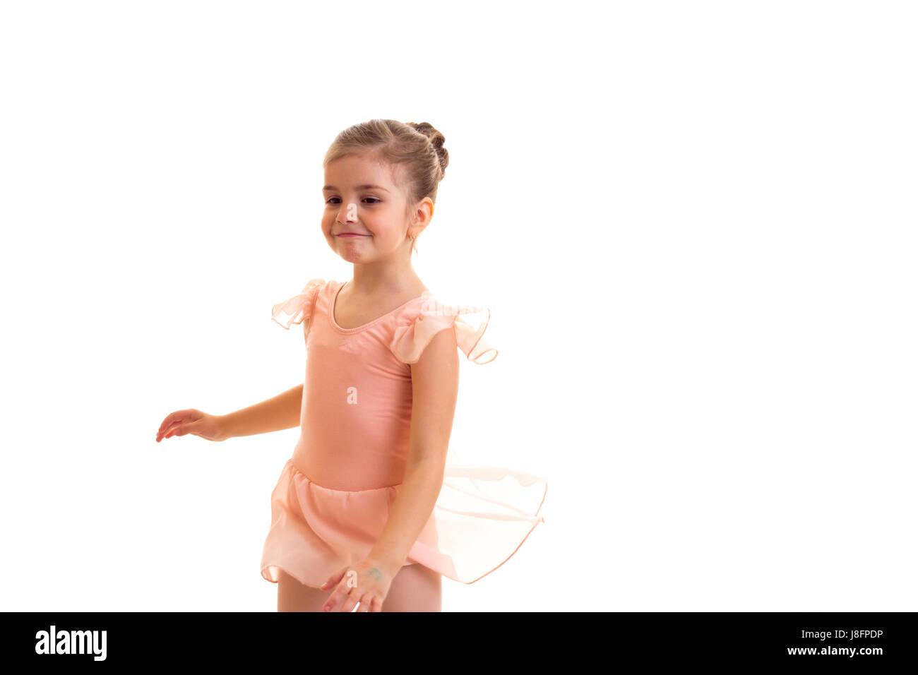 Smiling little girl in pink dress dancing on white background in studio ...