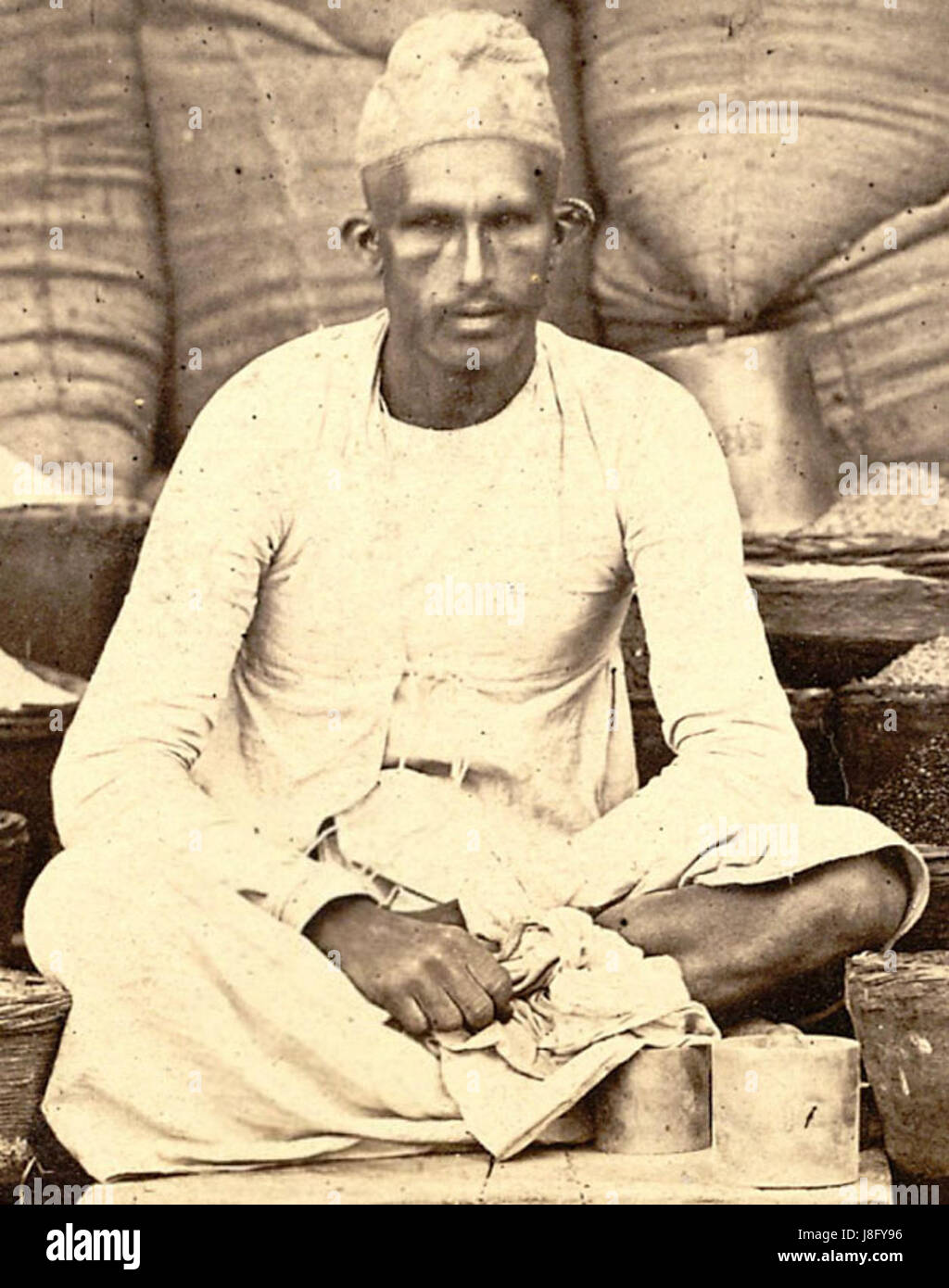 This historical image depicts a grain seller's shop in Bombay (now ...
