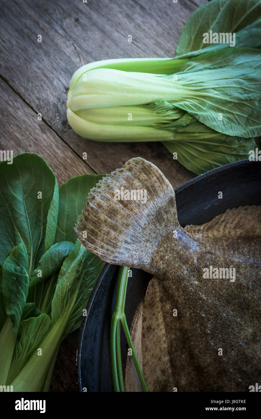 A closeup view of the tail of a turbot in a skillet; Pak choi ...