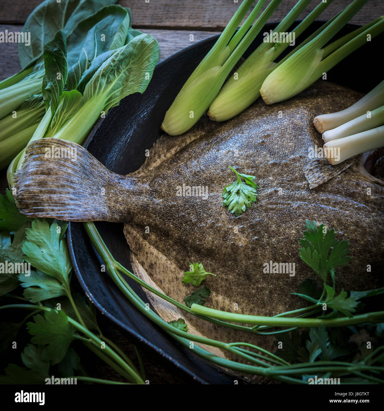 A closeup view of a turbot surrounded by baby vegetables; Food; Fish ...