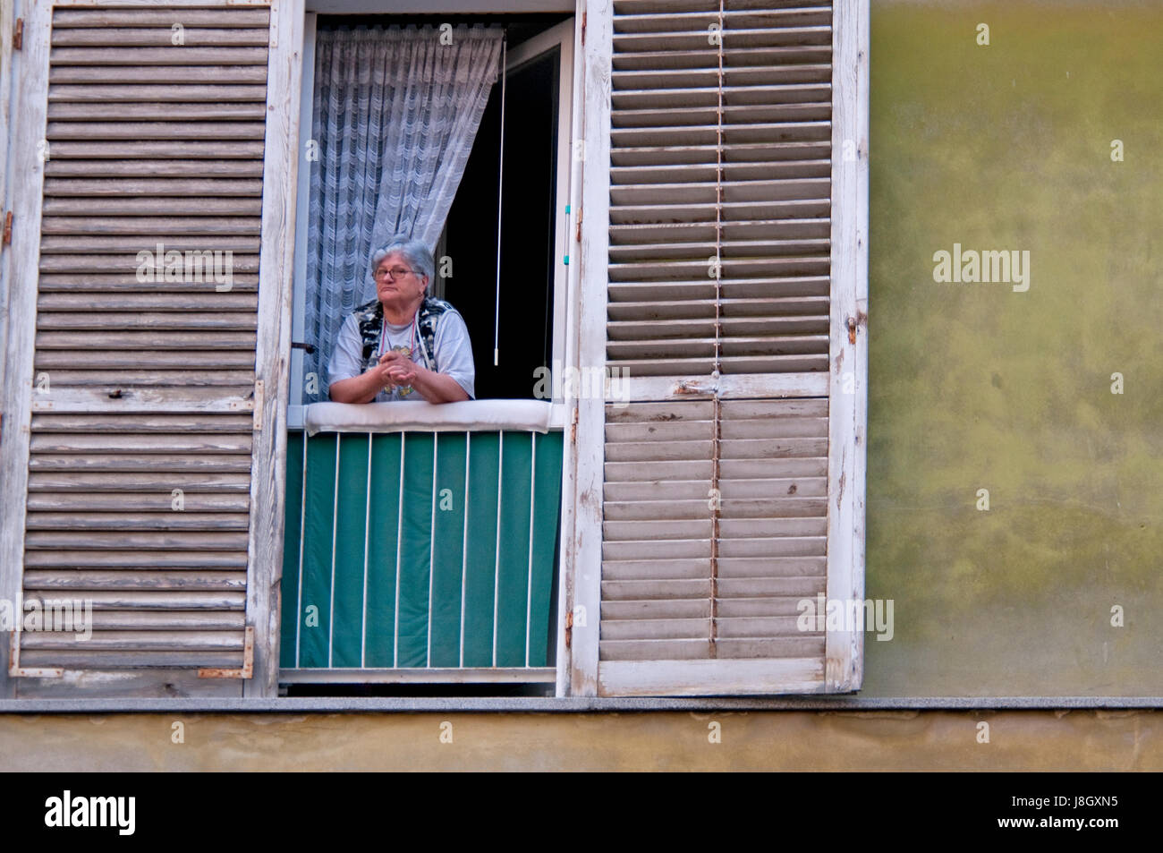 A senior woman looking out of her shutter window Stock Photo - Alamy