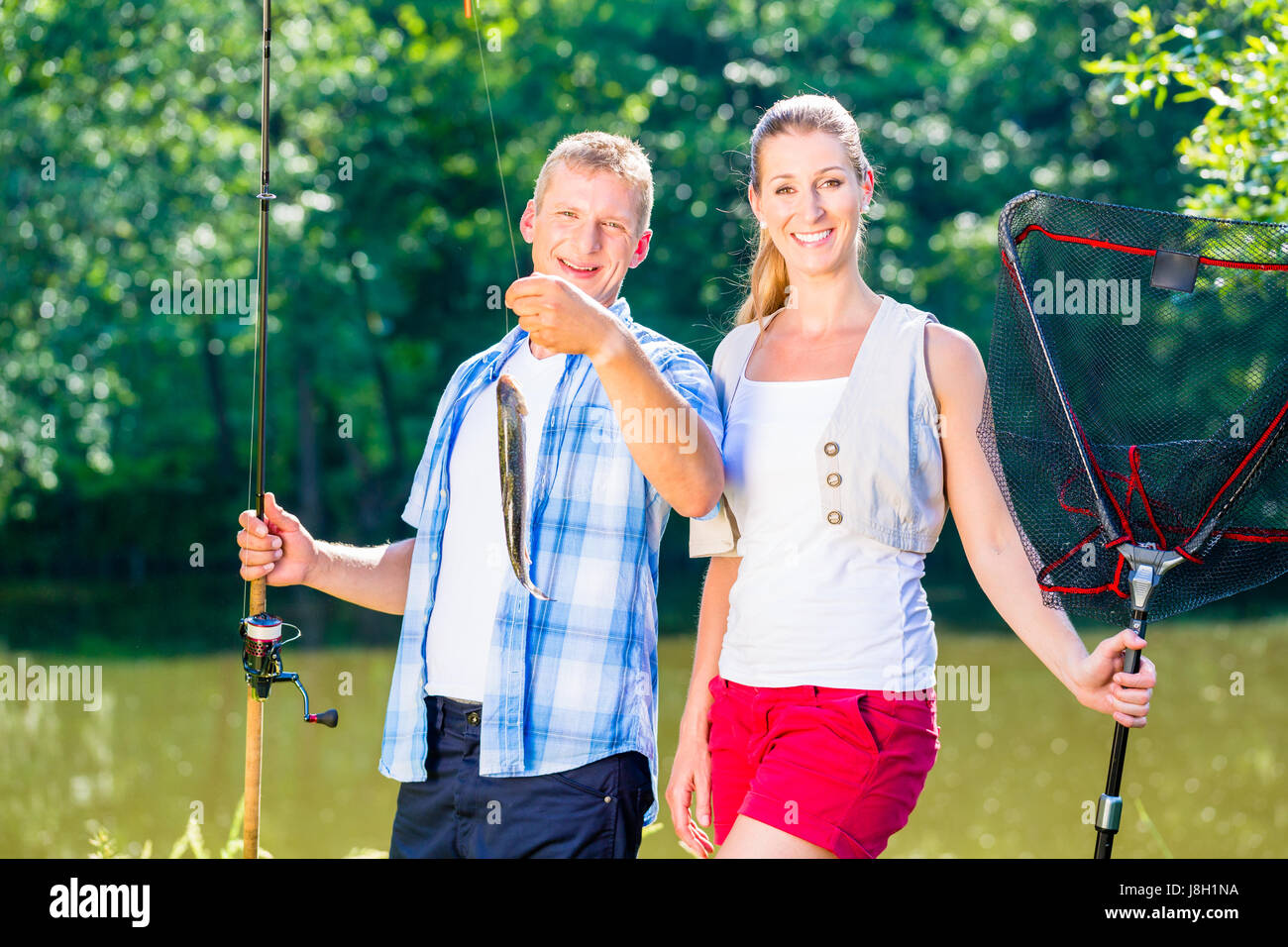 Fishing couple, man and woman, on lake being proud of catch Stock Photo ...