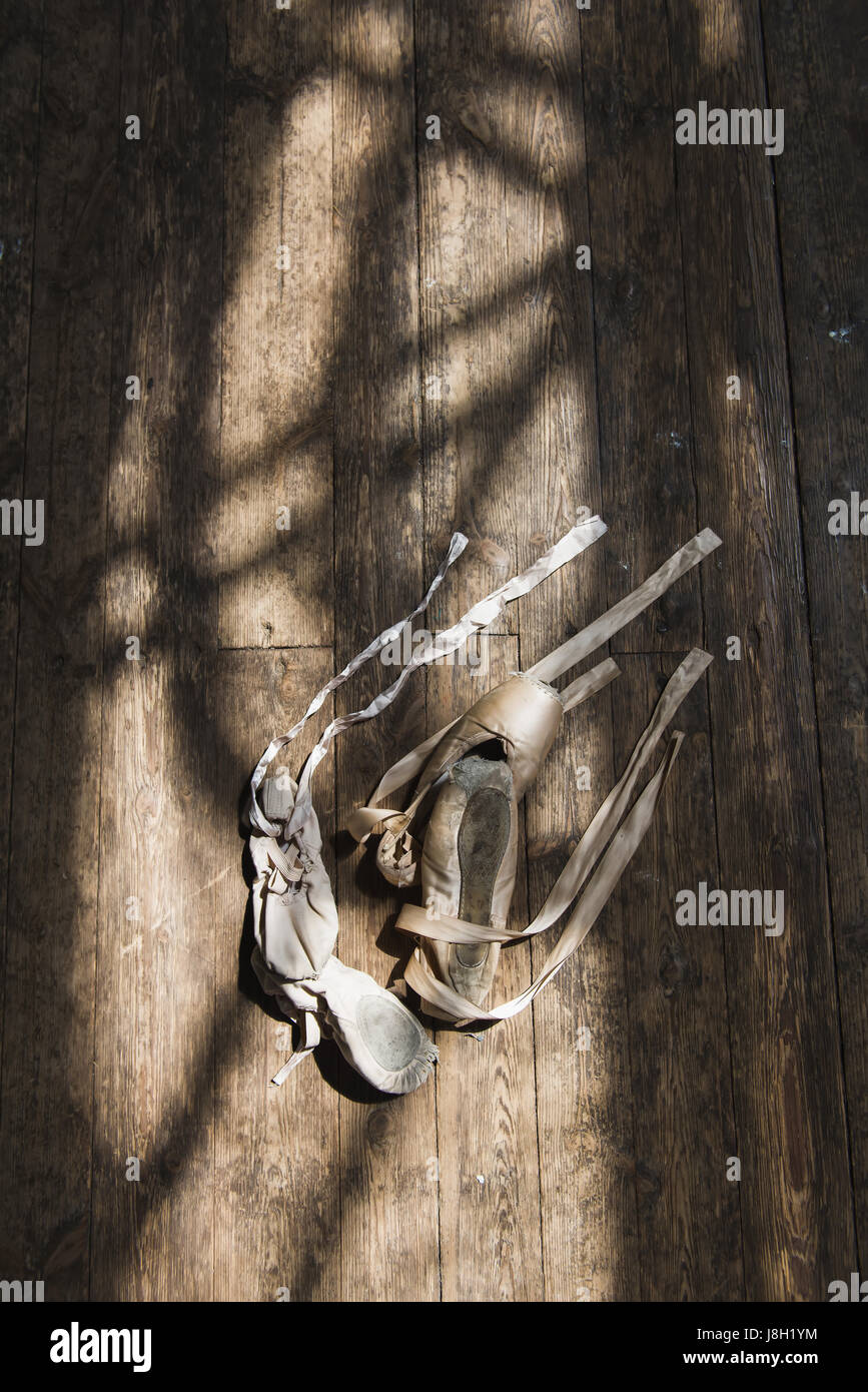 Old ballet shoes on old wooden floor. Pink ballet pointe. Shadow from ...