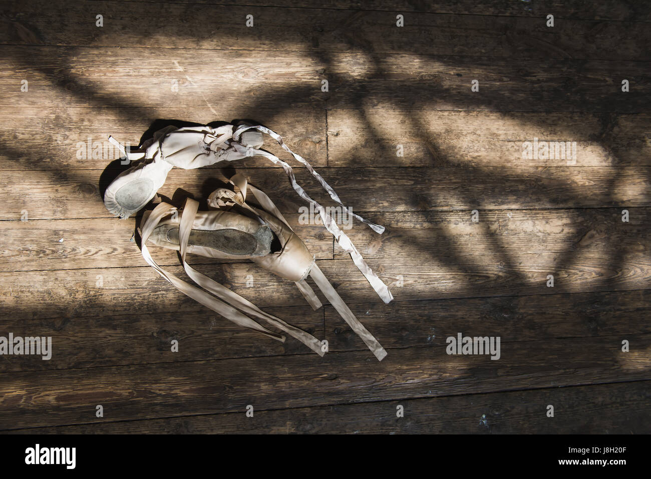 Old ballet shoes on old wooden floor. Pink ballet pointe. Shadow from ...