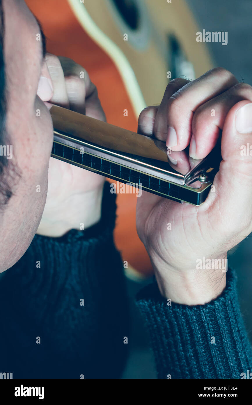 Young man blowing harmonica Musical Fun Stock Photo - Alamy