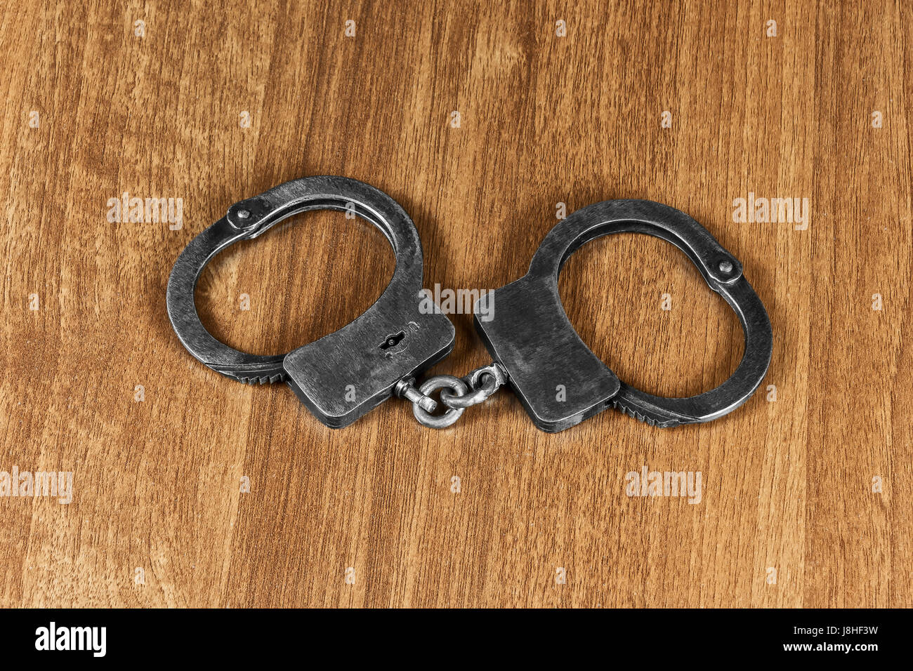 Police handcuffs lie on a wooden table Stock Photo - Alamy