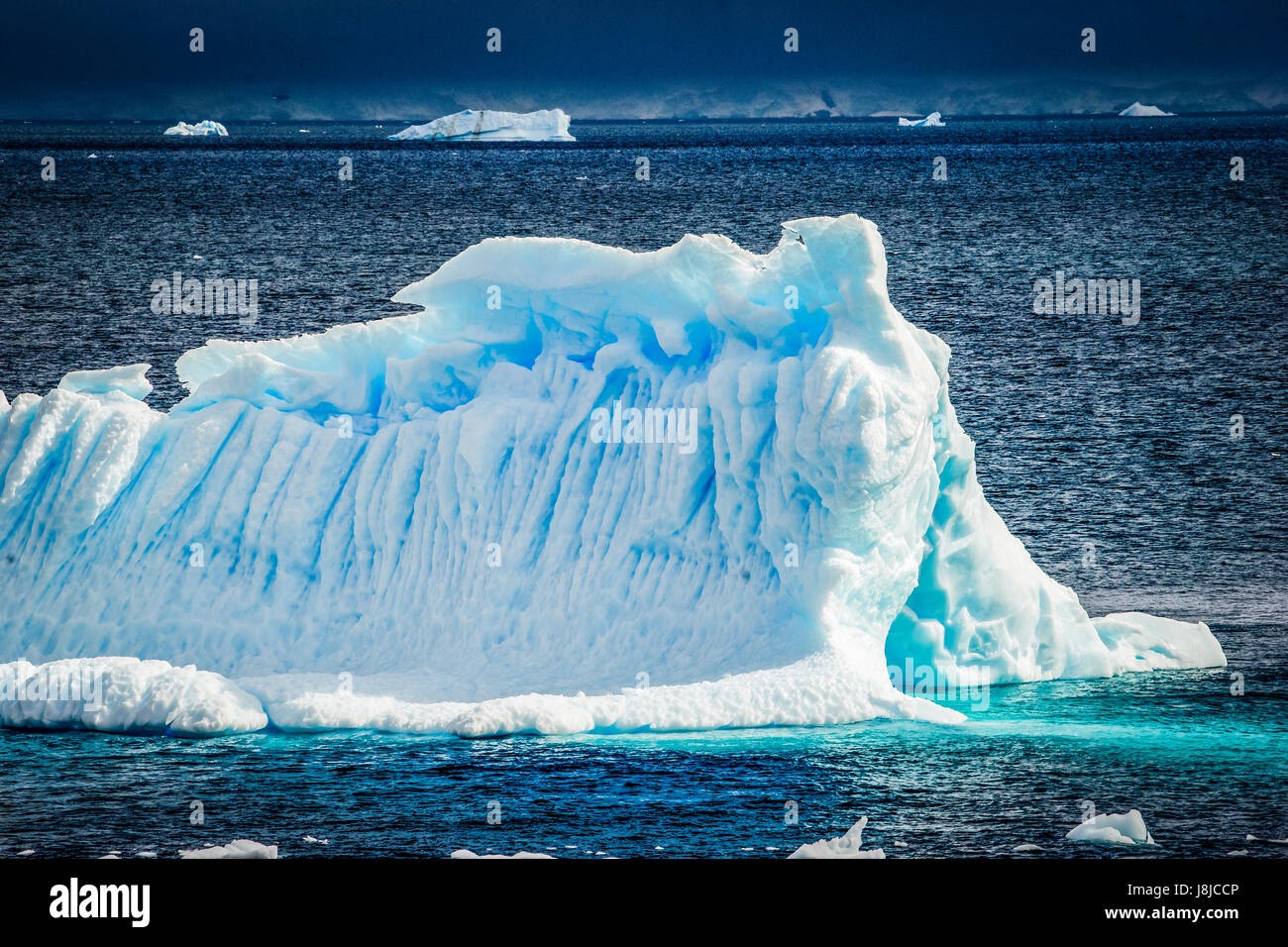A ray of light shines right on this bergy bit iceberg under a stormy ...