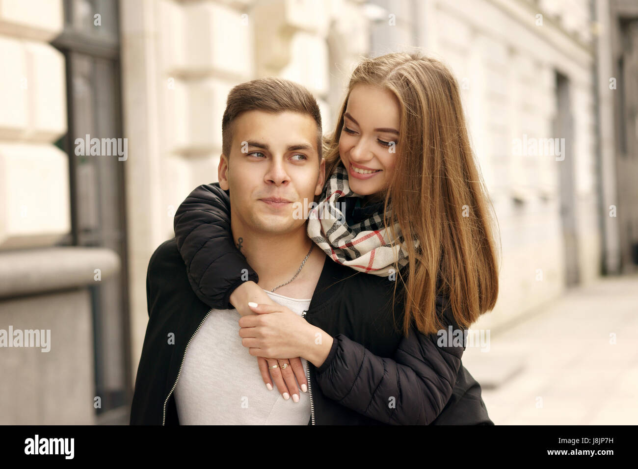 Young happy joyous couple cuddling at city street. Beautiful pretty ...