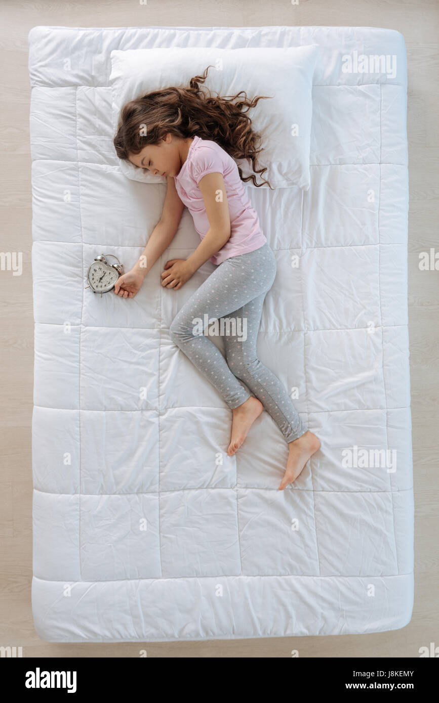 Time to wake up. Top view of a nice pleasant cute girl lying near the ...