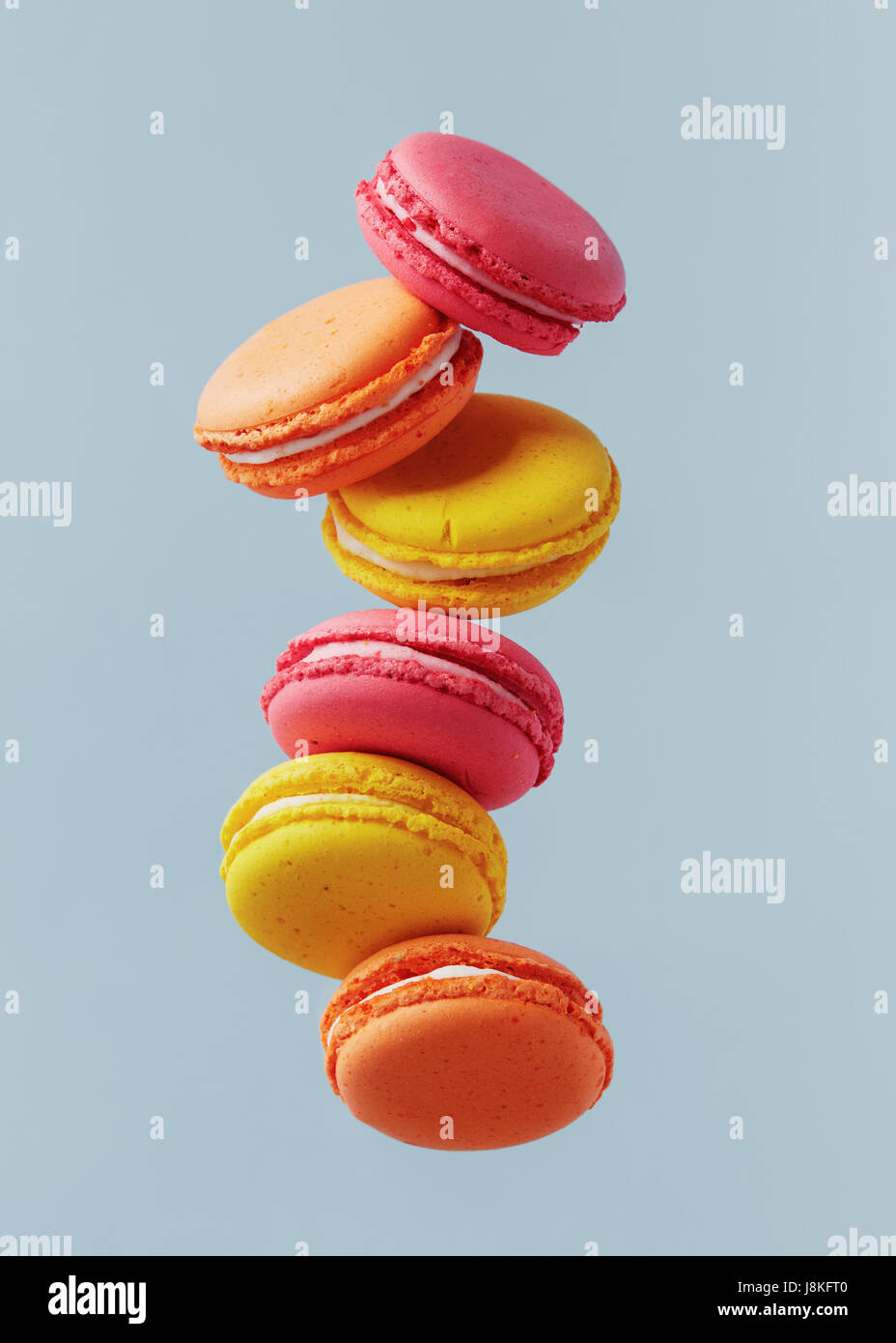 Different types of macaroons in motion falling on light blue background ...