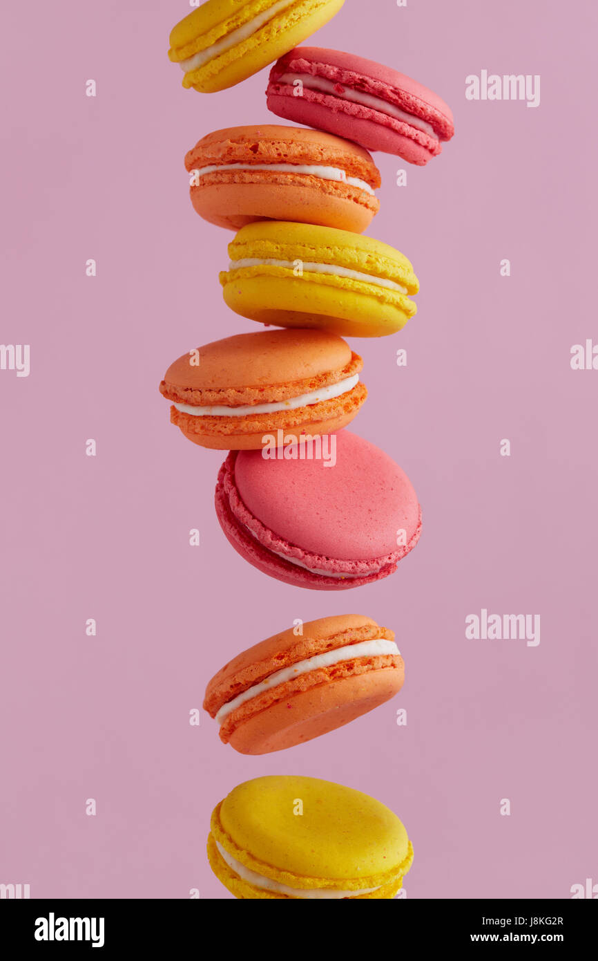 Different types of macaroons in motion falling on pink background ...