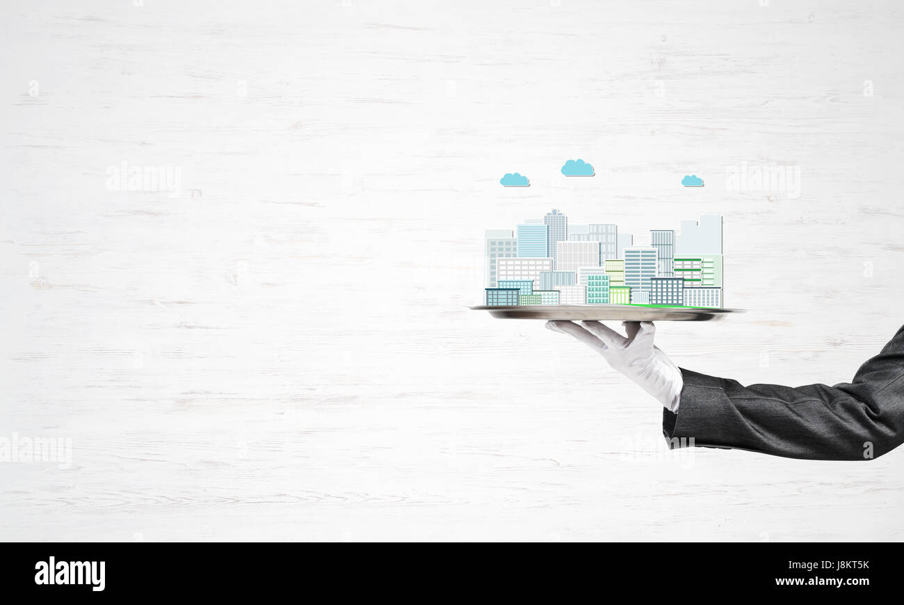 Hand holding metal tray with modern city model against wooden ...