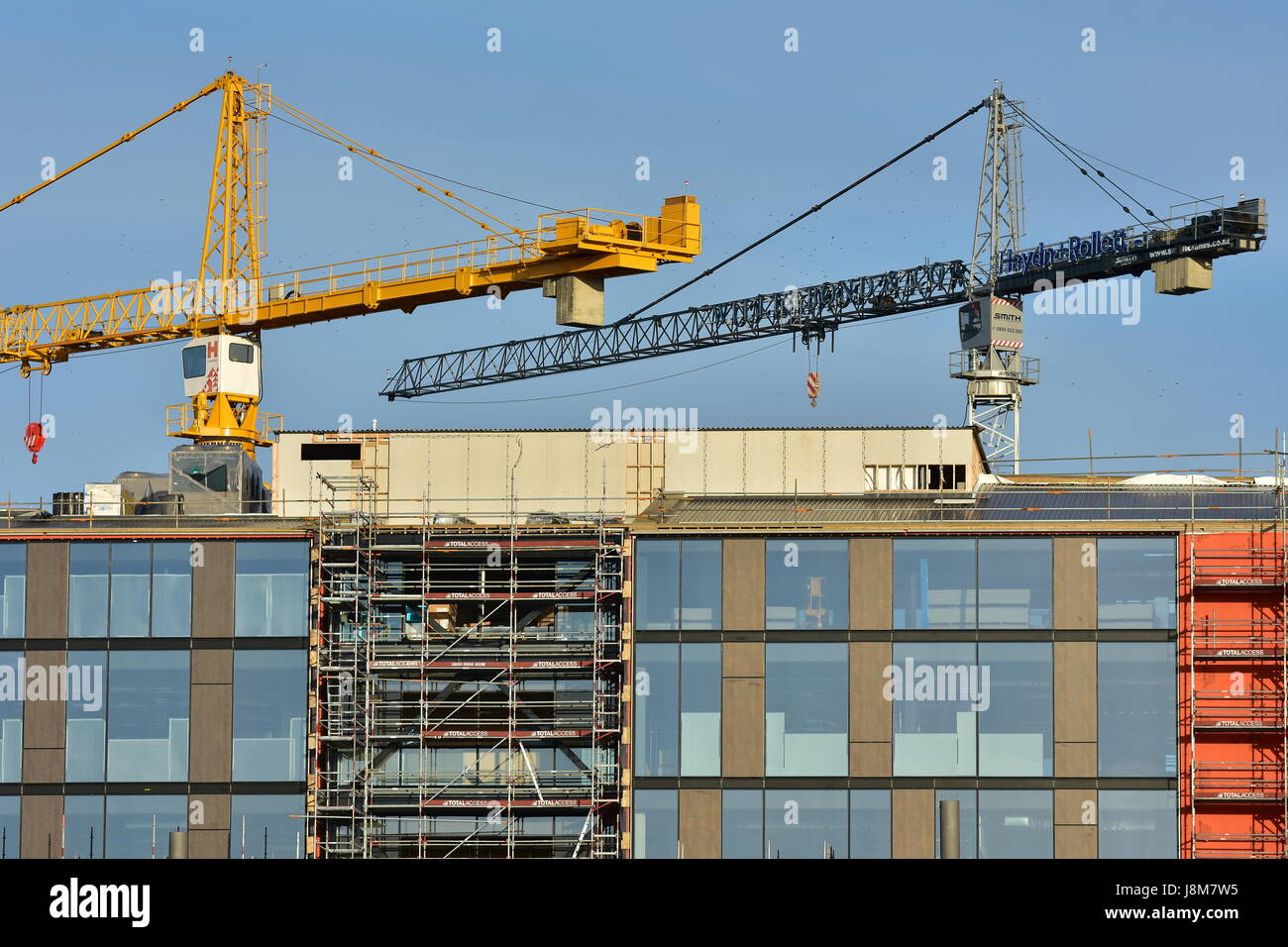Two tower cranes above modern office building construction site Stock ...