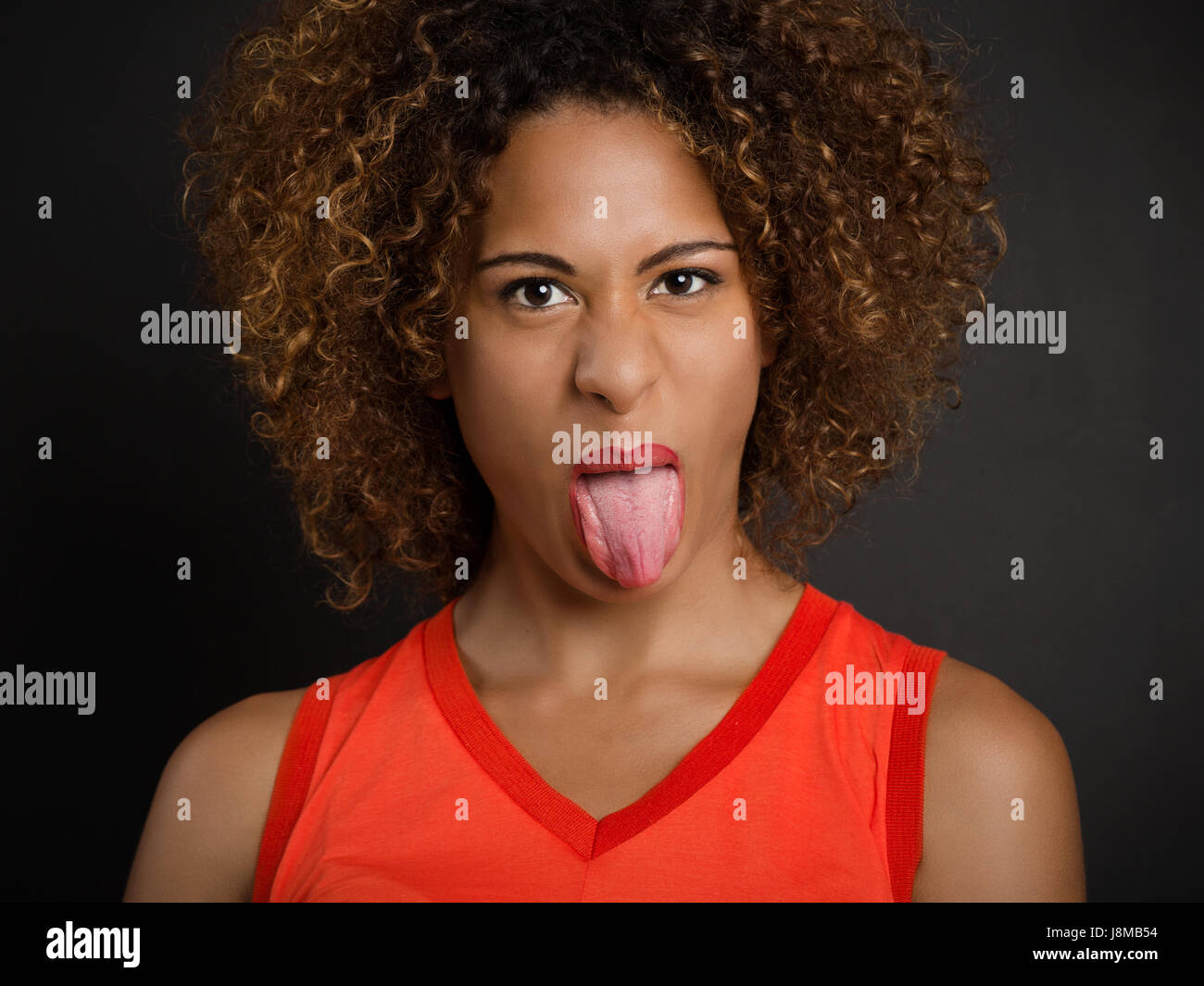 Portrait of a beautiful African American woman pulling her tongue out ...