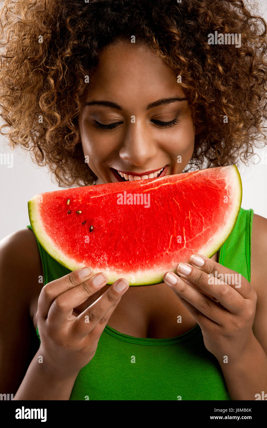 Beautiful African American woman olding and eating a watermelon fruit ...