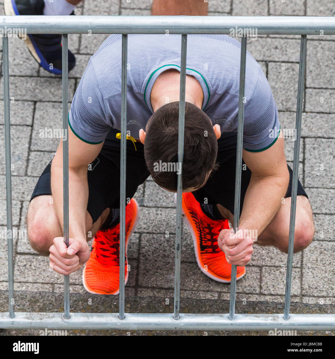 A young adult crouches down and catches his breath after finishing the ...